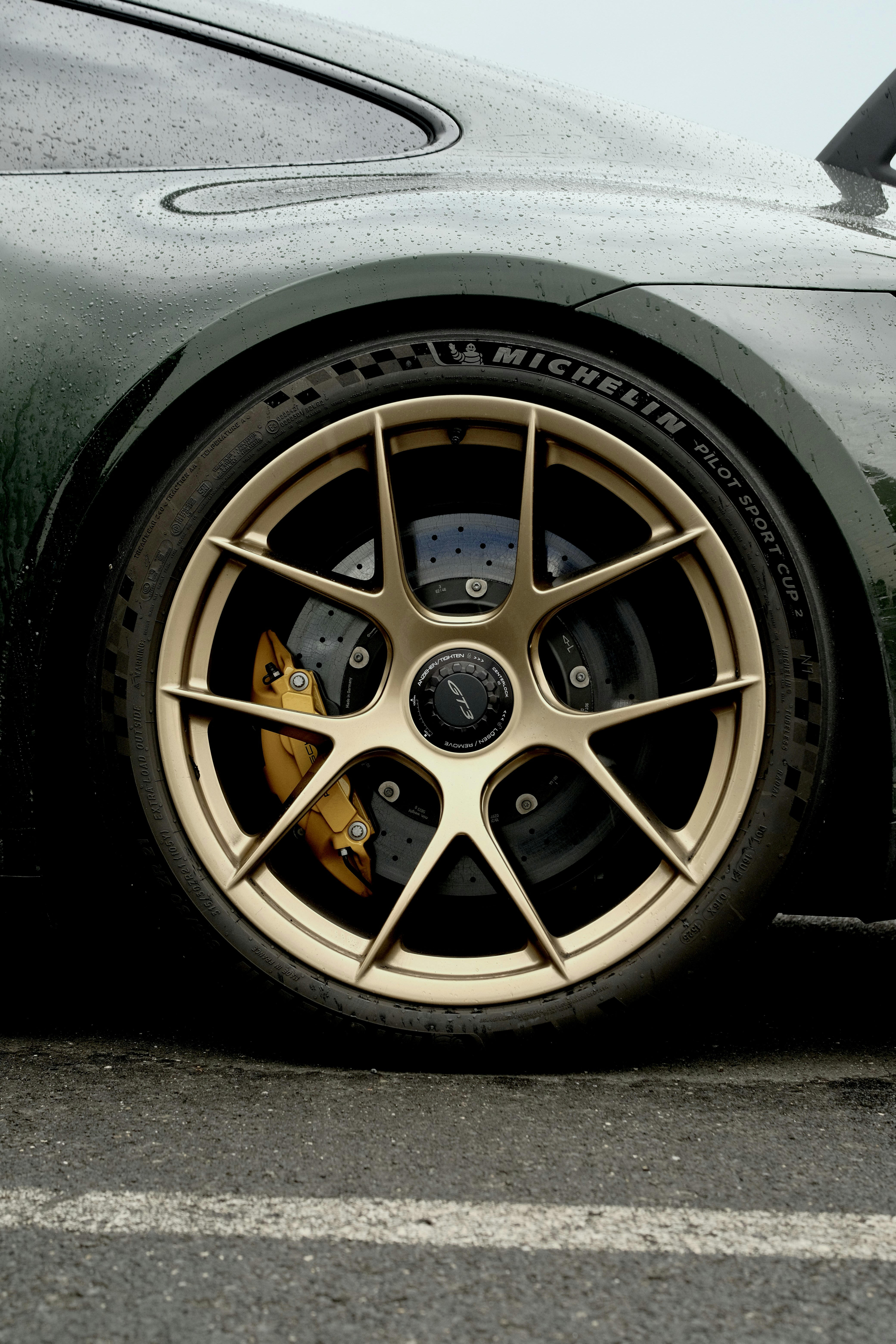 Golden spokes and carbon brakes: a Porsche wheel close-up in rain