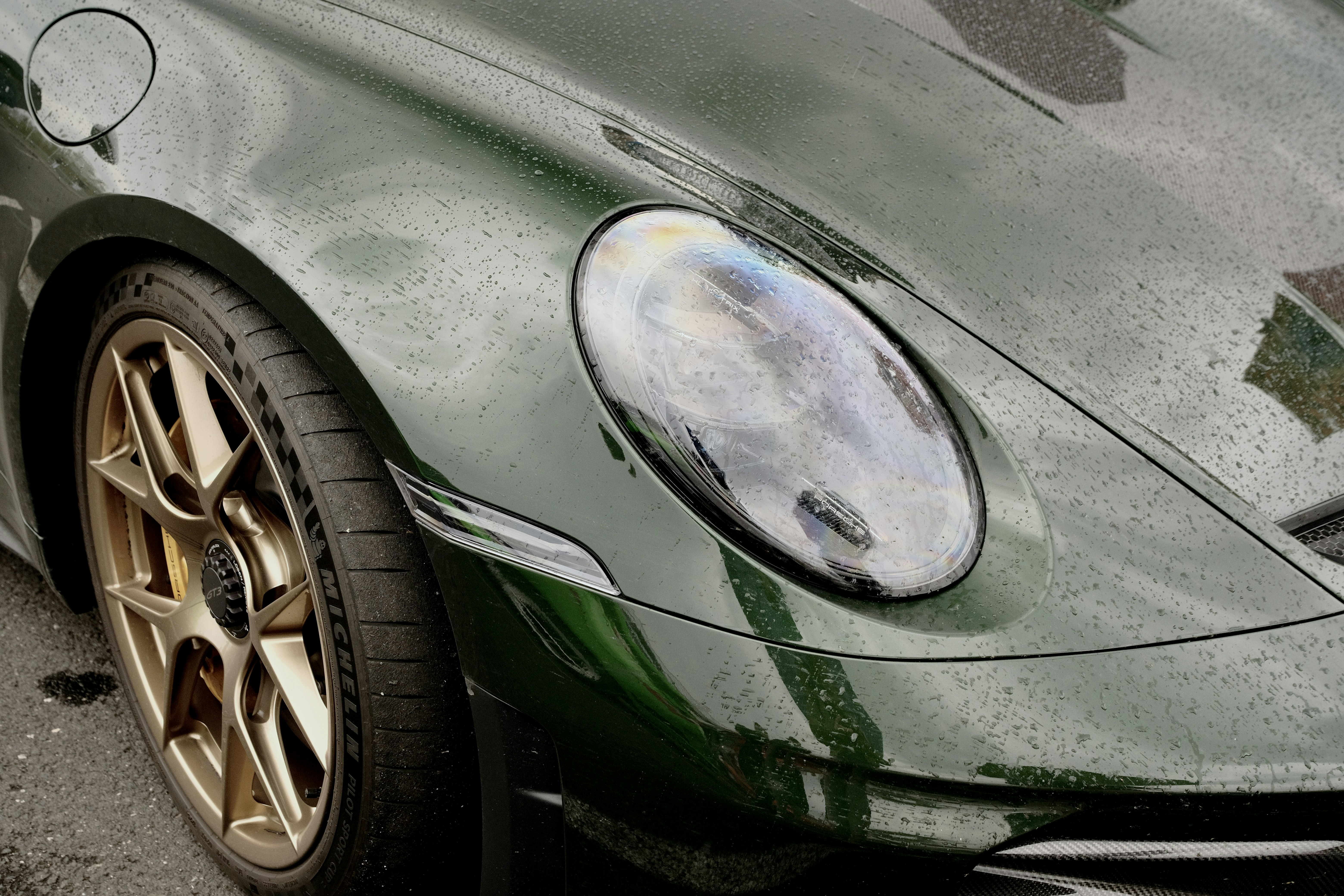 Green Porsche in Rain: A Close-Focus on the Headlight Hue