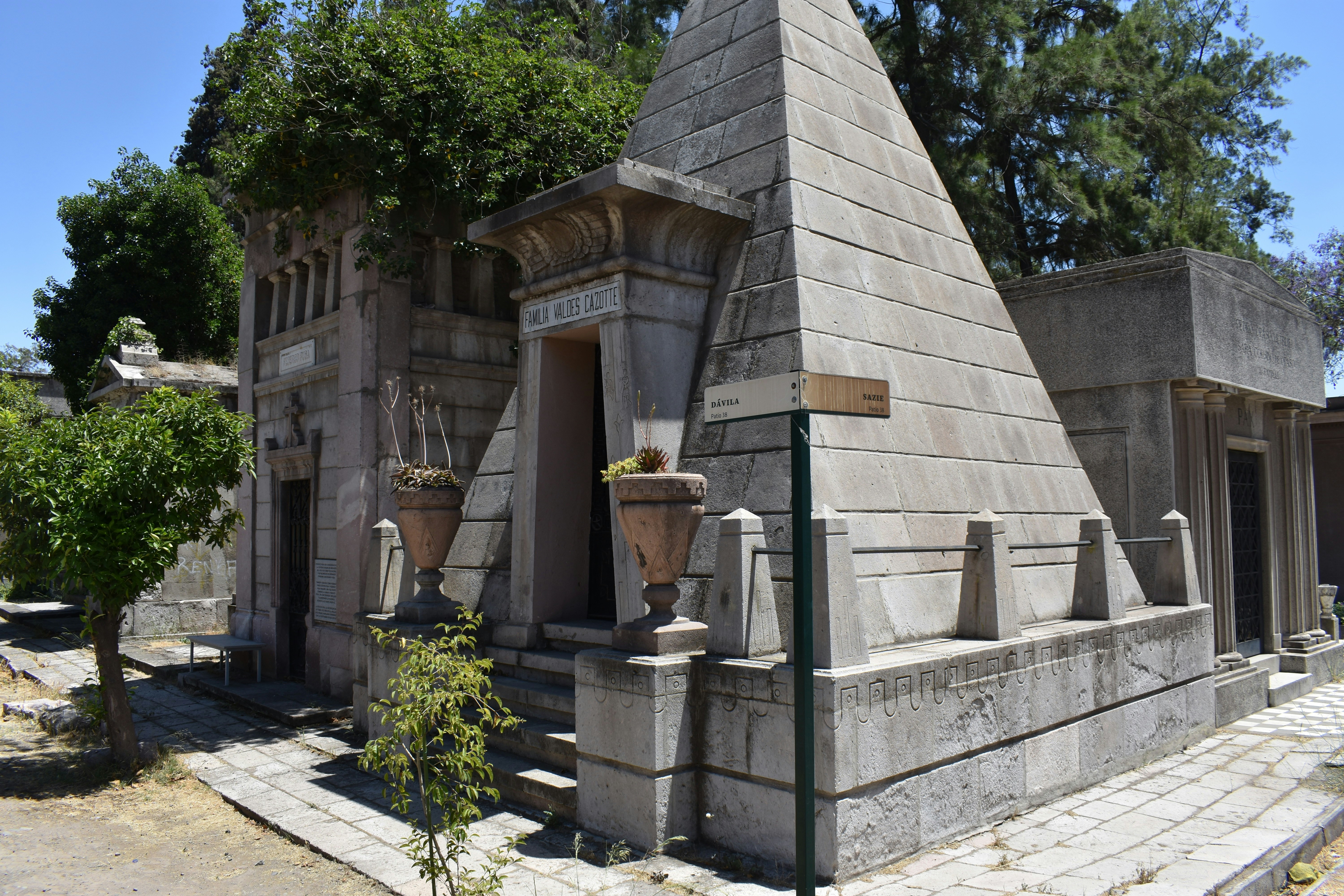 Sunlit Mausoleum Corners: Carved Trench and Pyramid Leaning in a Quiet Cemetery