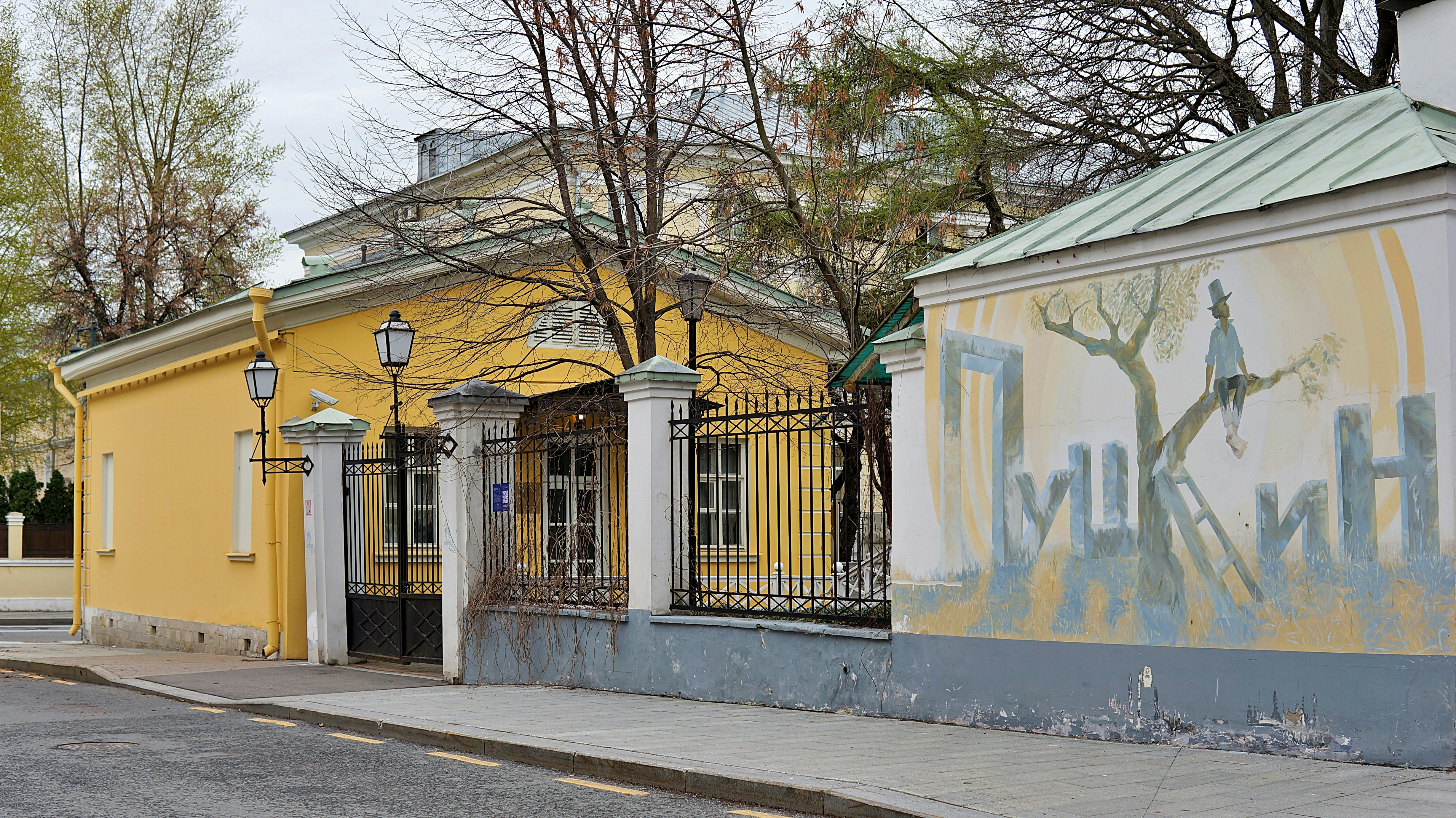 Yellow Villa Gate with Mural Wall under Leafy Trees