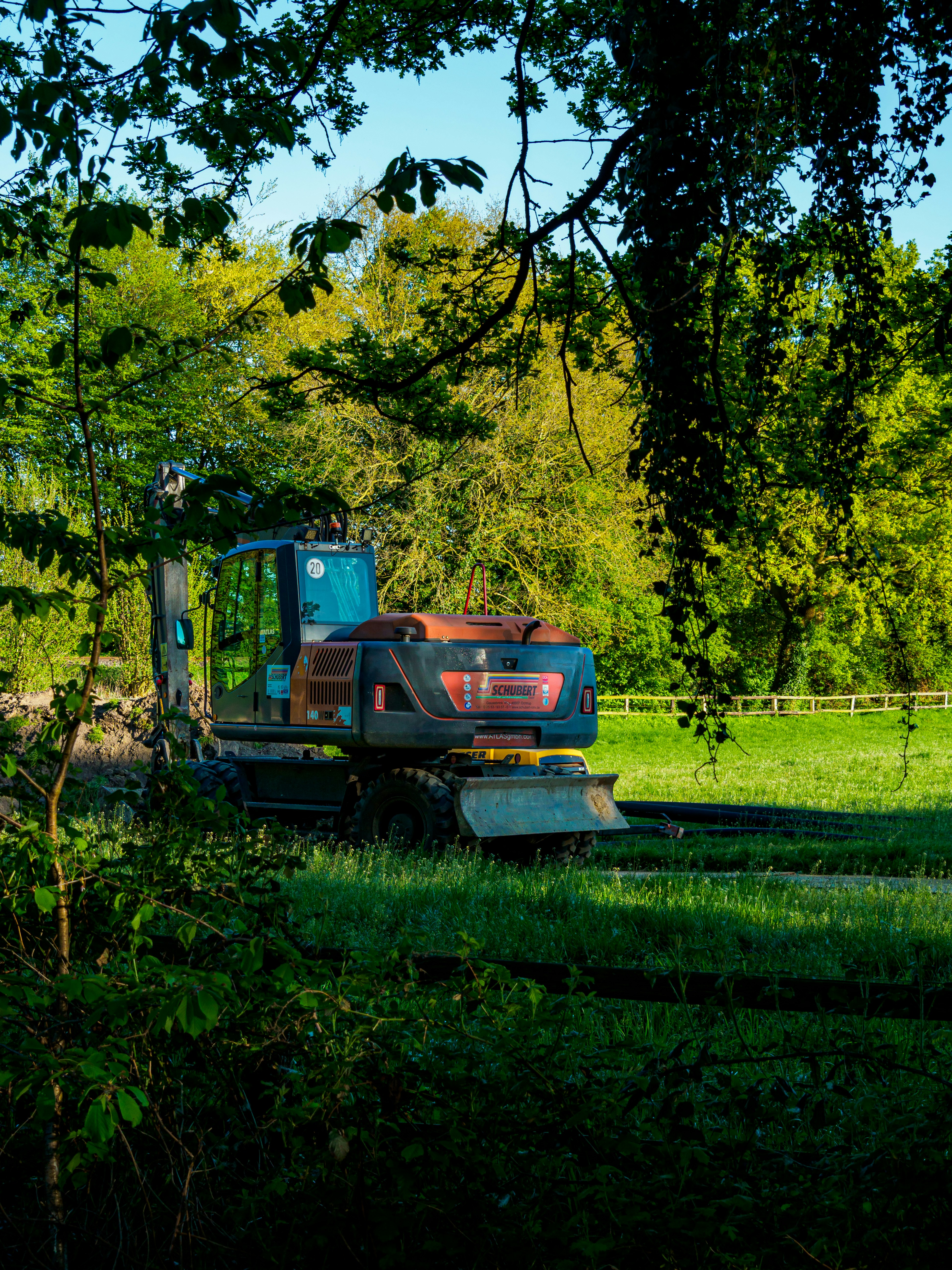 Blue Excavator Resting in a Sunlit Clearing