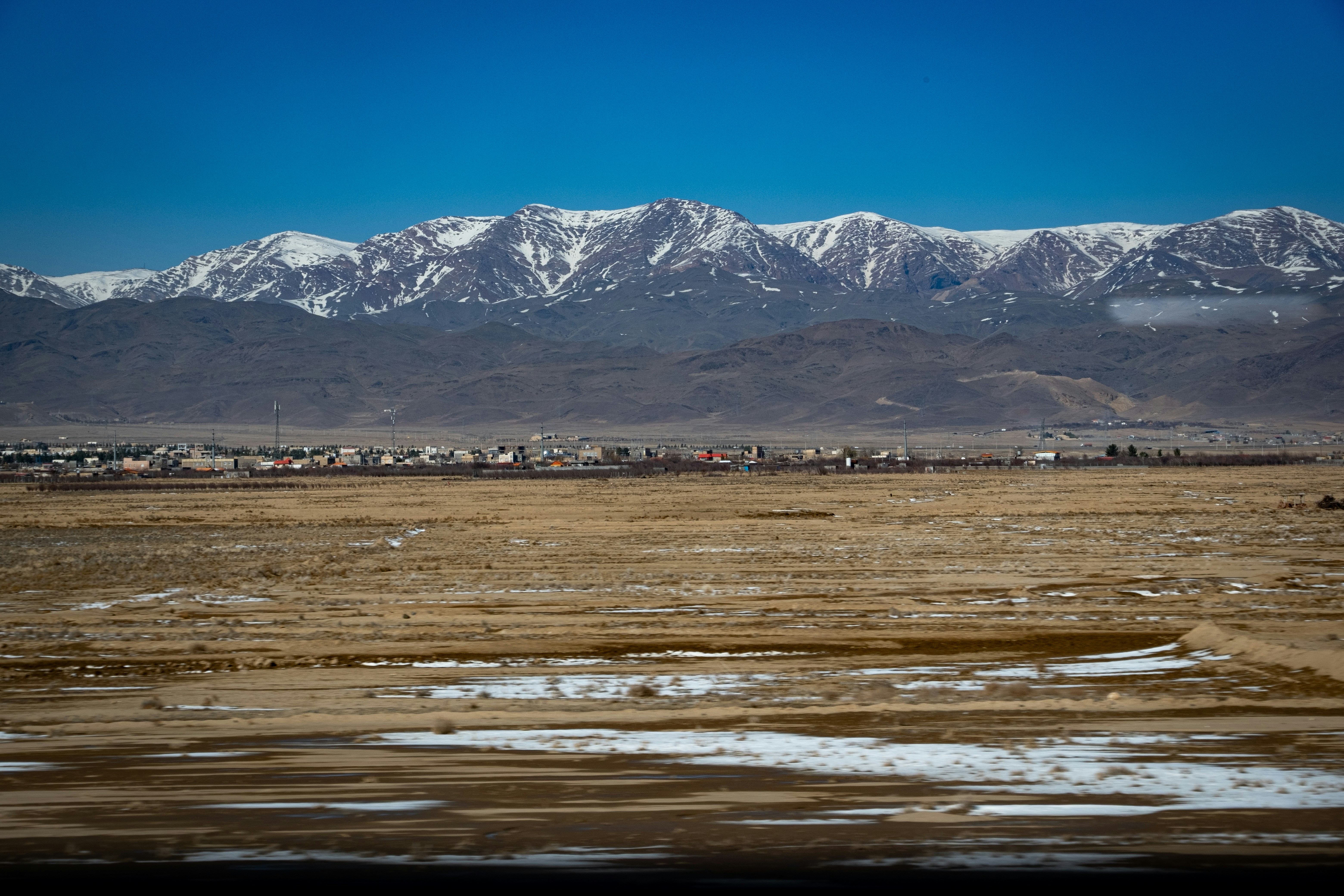 Snow-capped mountains rise above a barren, dry landscape. photo – Free ...