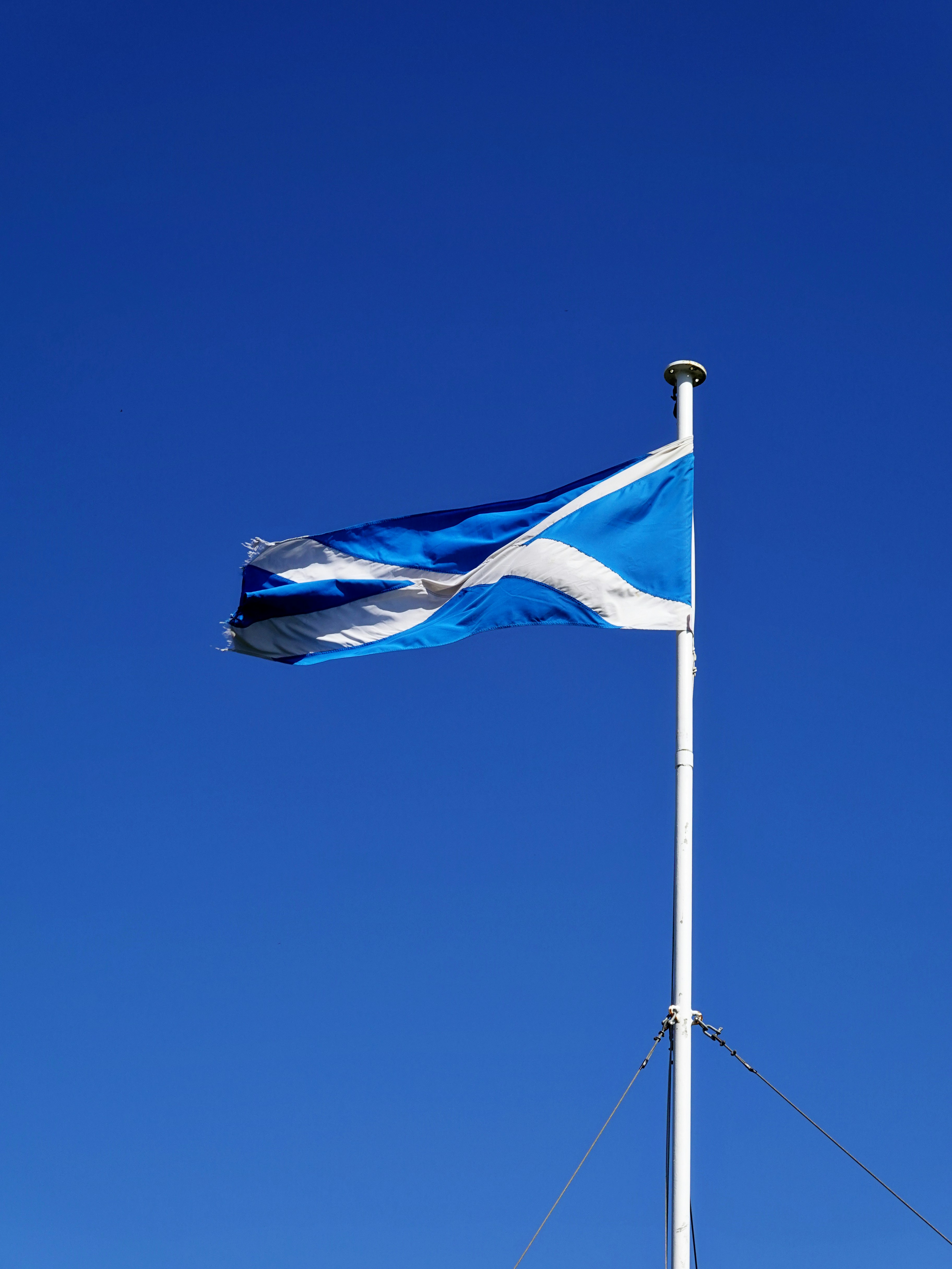 Flag of Scotland against a pristine blue sky on a tall mast