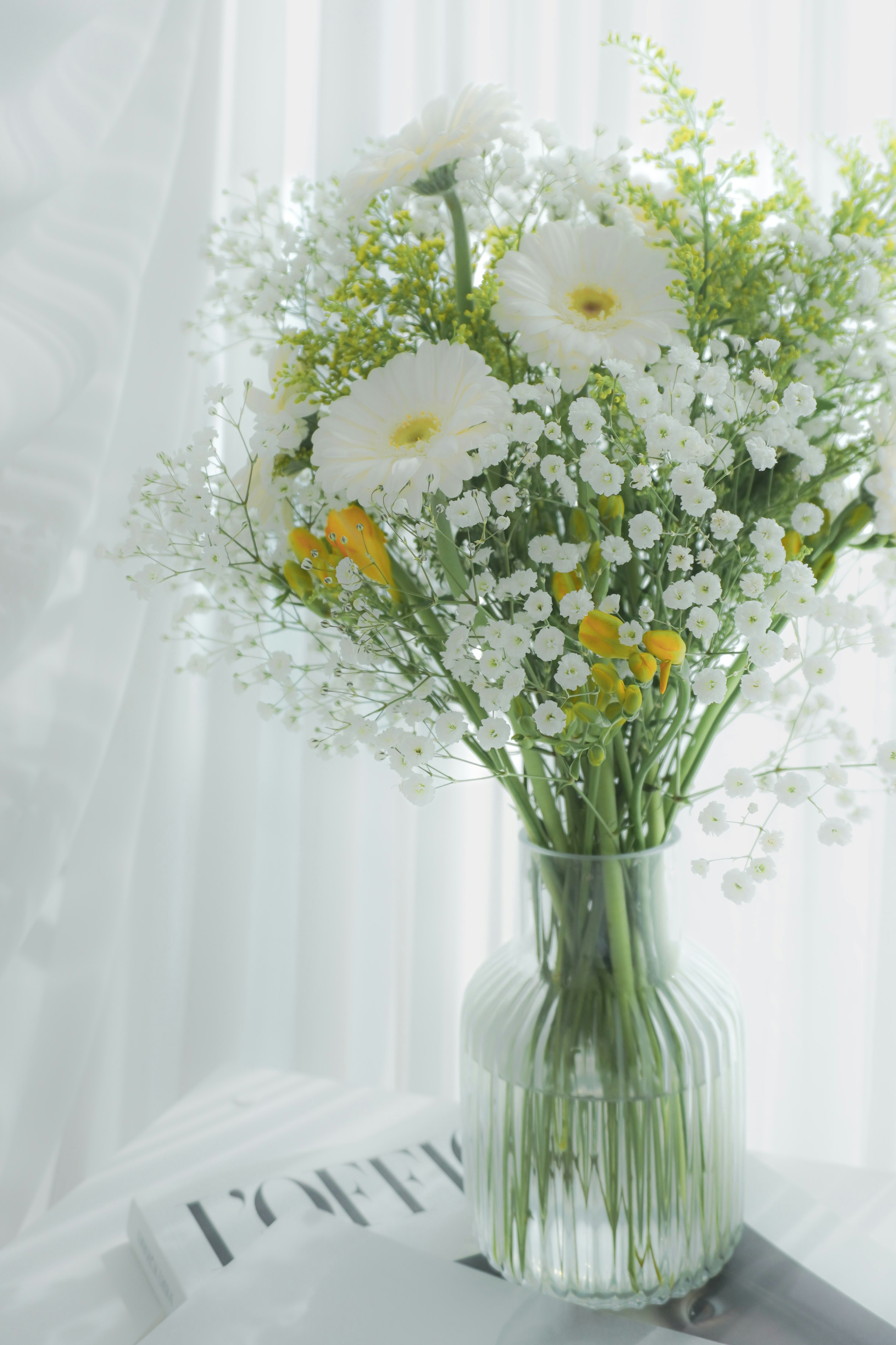 Petal bouquet in a ribbed glass vase bathed in soft backlight