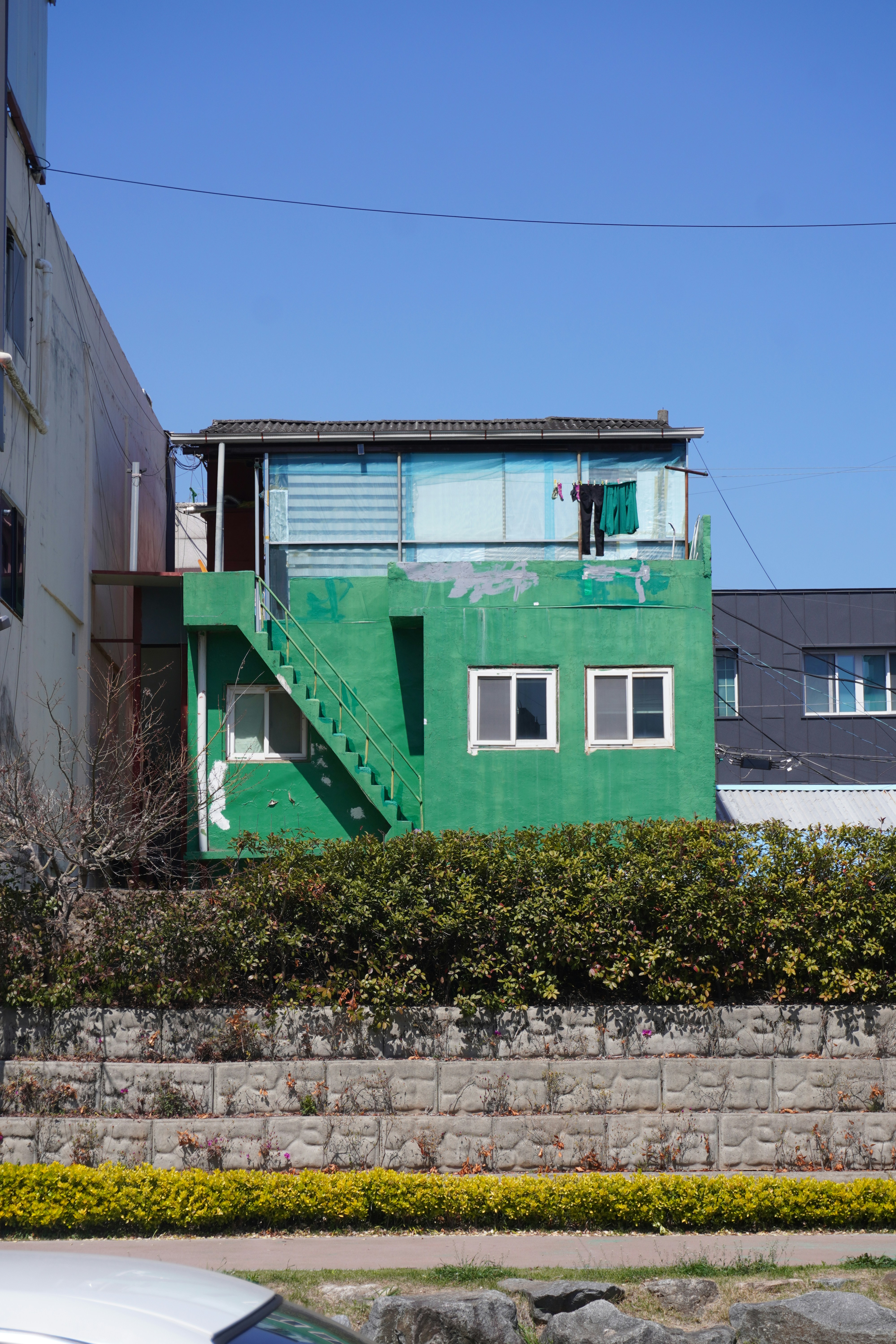 Green Apartment Studio: A Bright Urban Facade with Stairs and Laundry