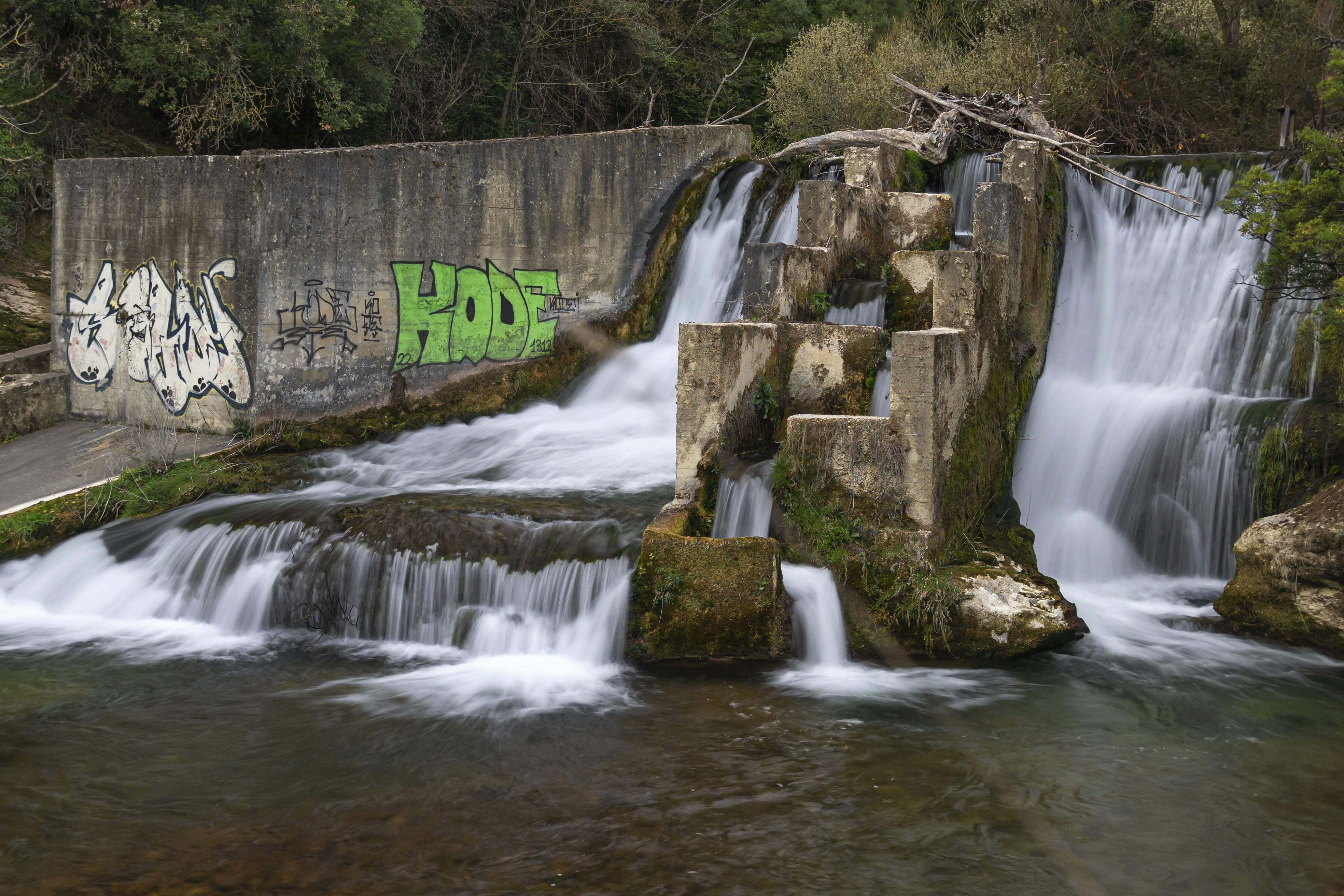 Concrete Cascade: Graffiti and Waterfall Meet in Quiet Quarry