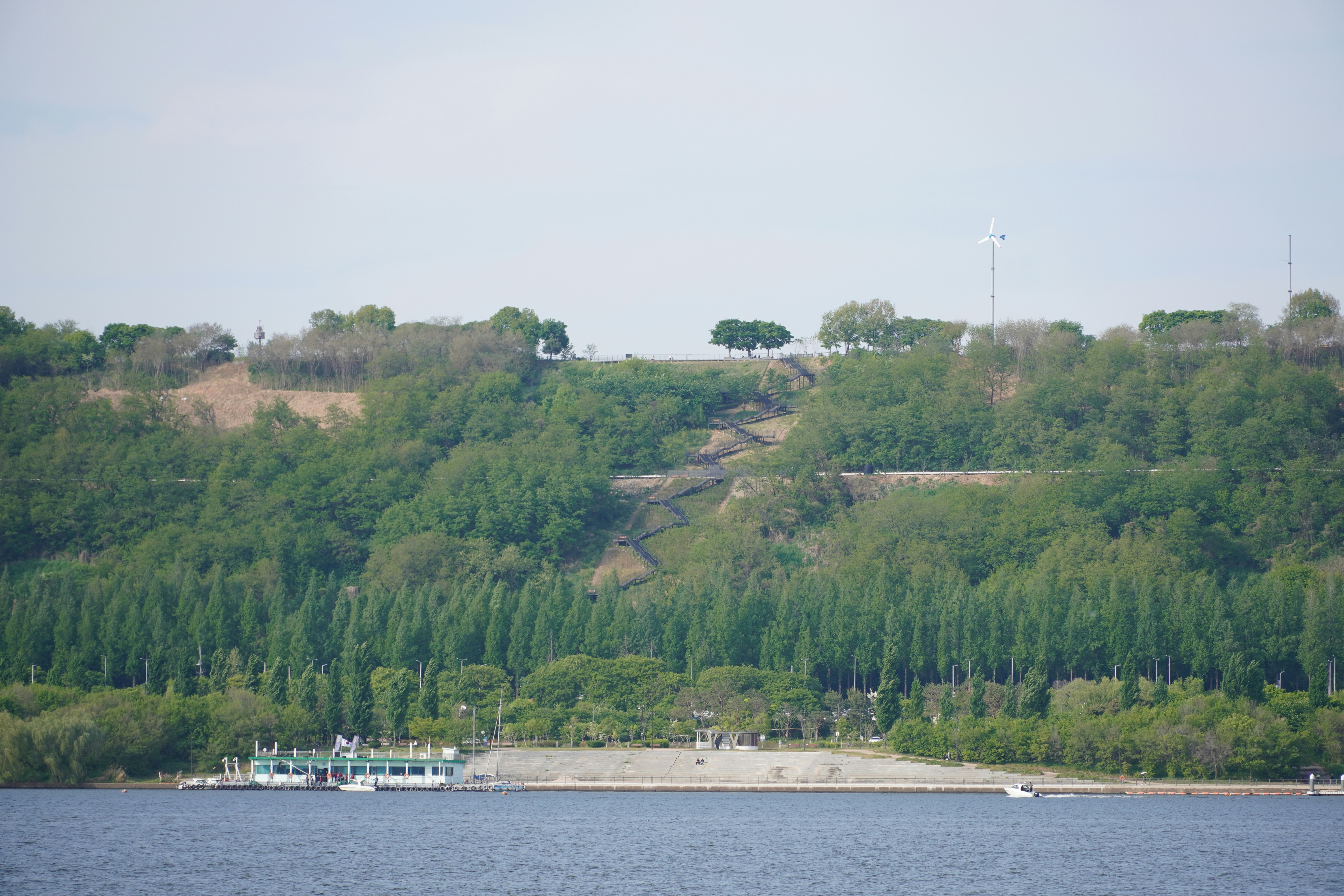 Riverside Hillscape with Wind Turbine and Distant Trees