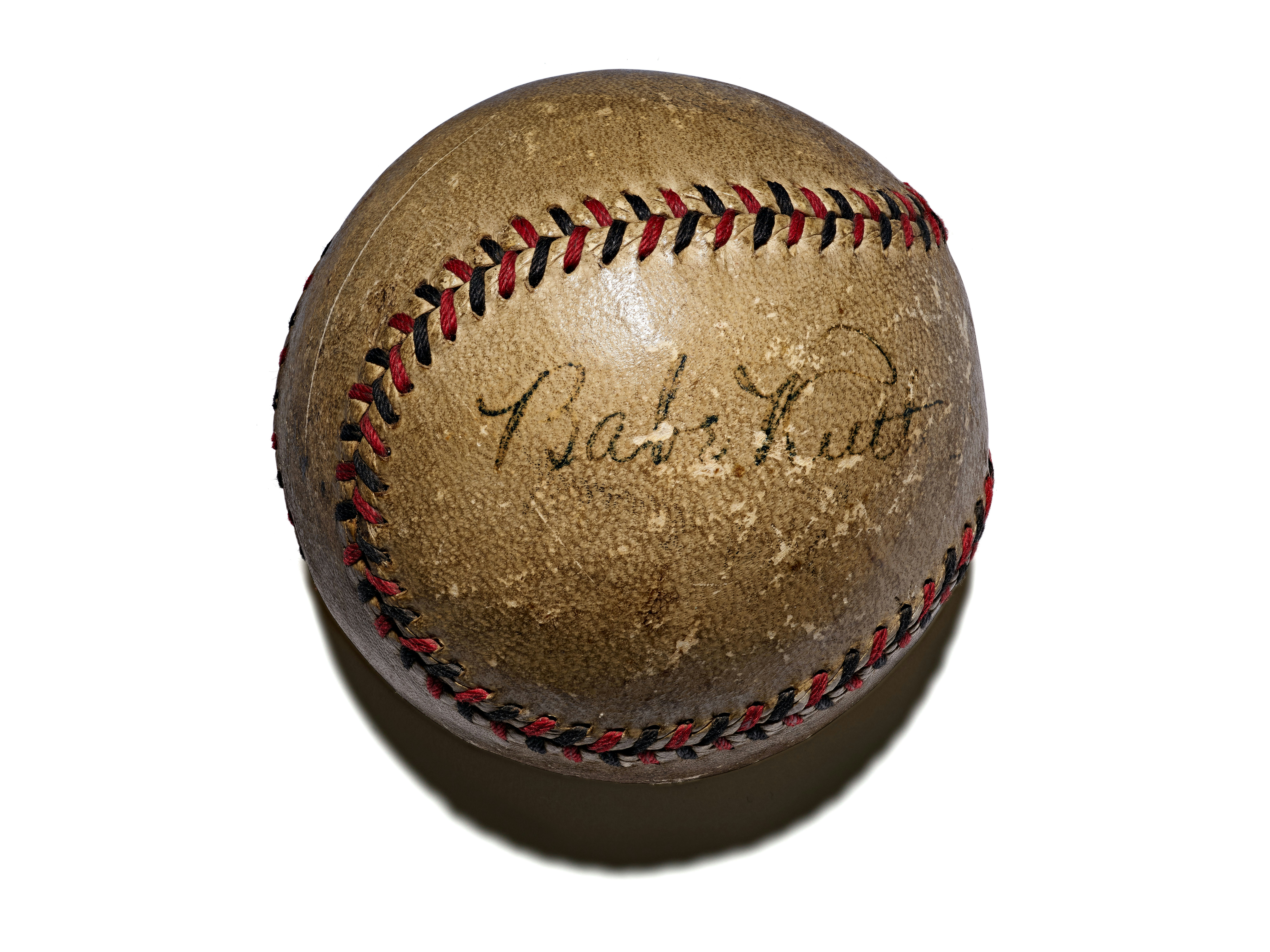 A weathered baseball with visible stitching sits against a plain backdrop, its faded autograph hinting at a bygone game. This neutral presentation emphasizes texture and character without context.