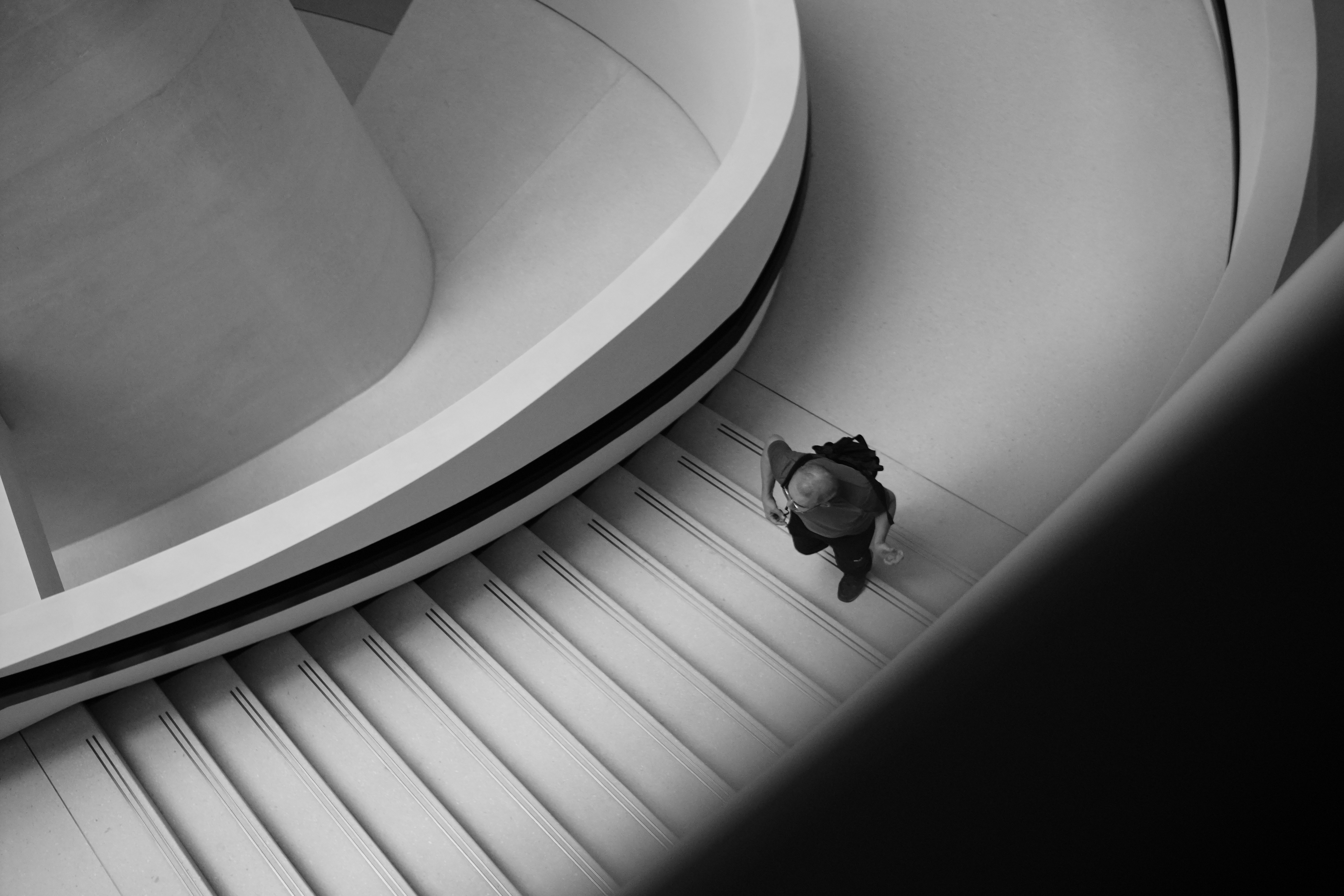 Spiral Vaults: A Lone Figure Descends the Concrete Staircase