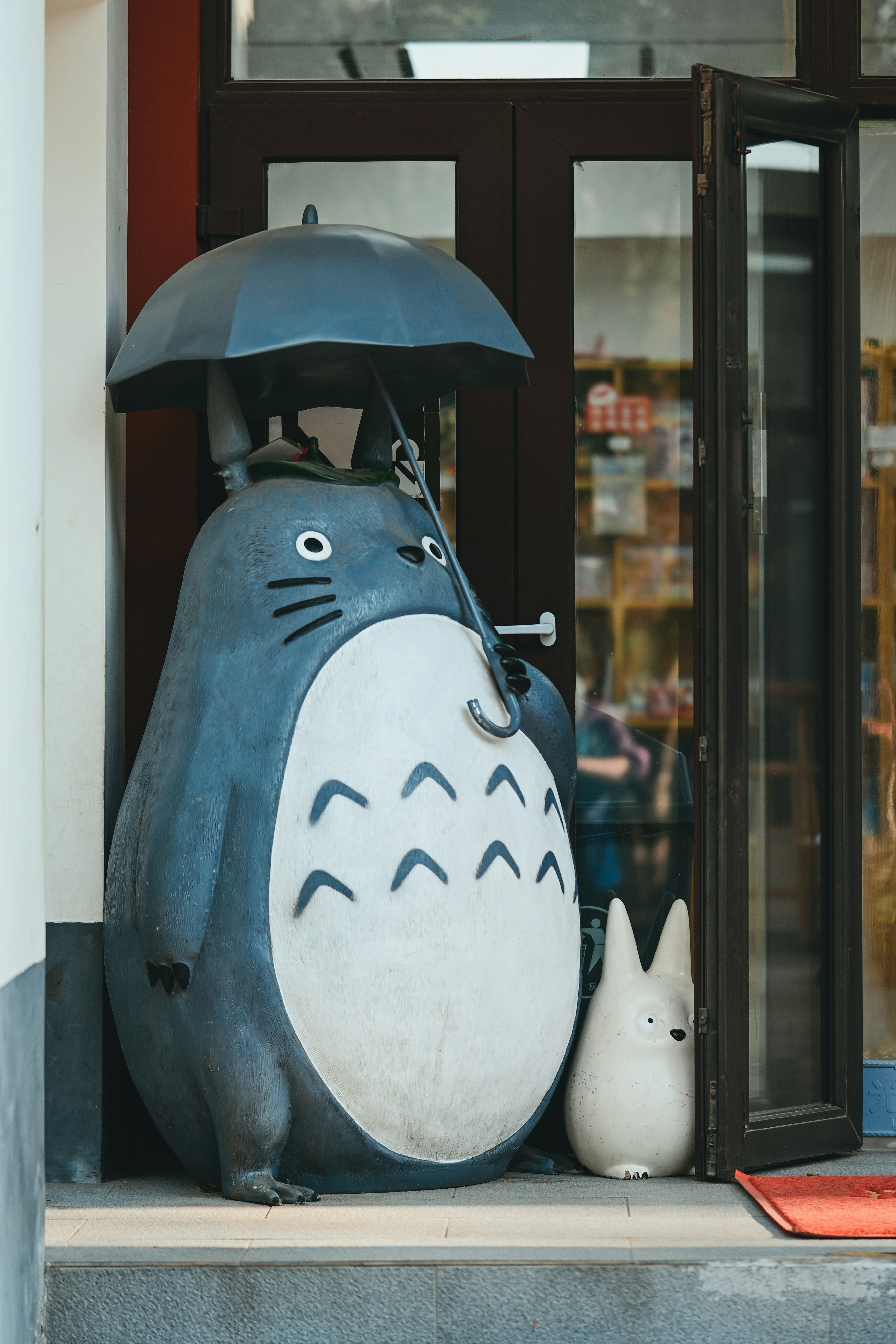 Totem of Shelter: A Totoro-like statue with an umbrella at the doorway