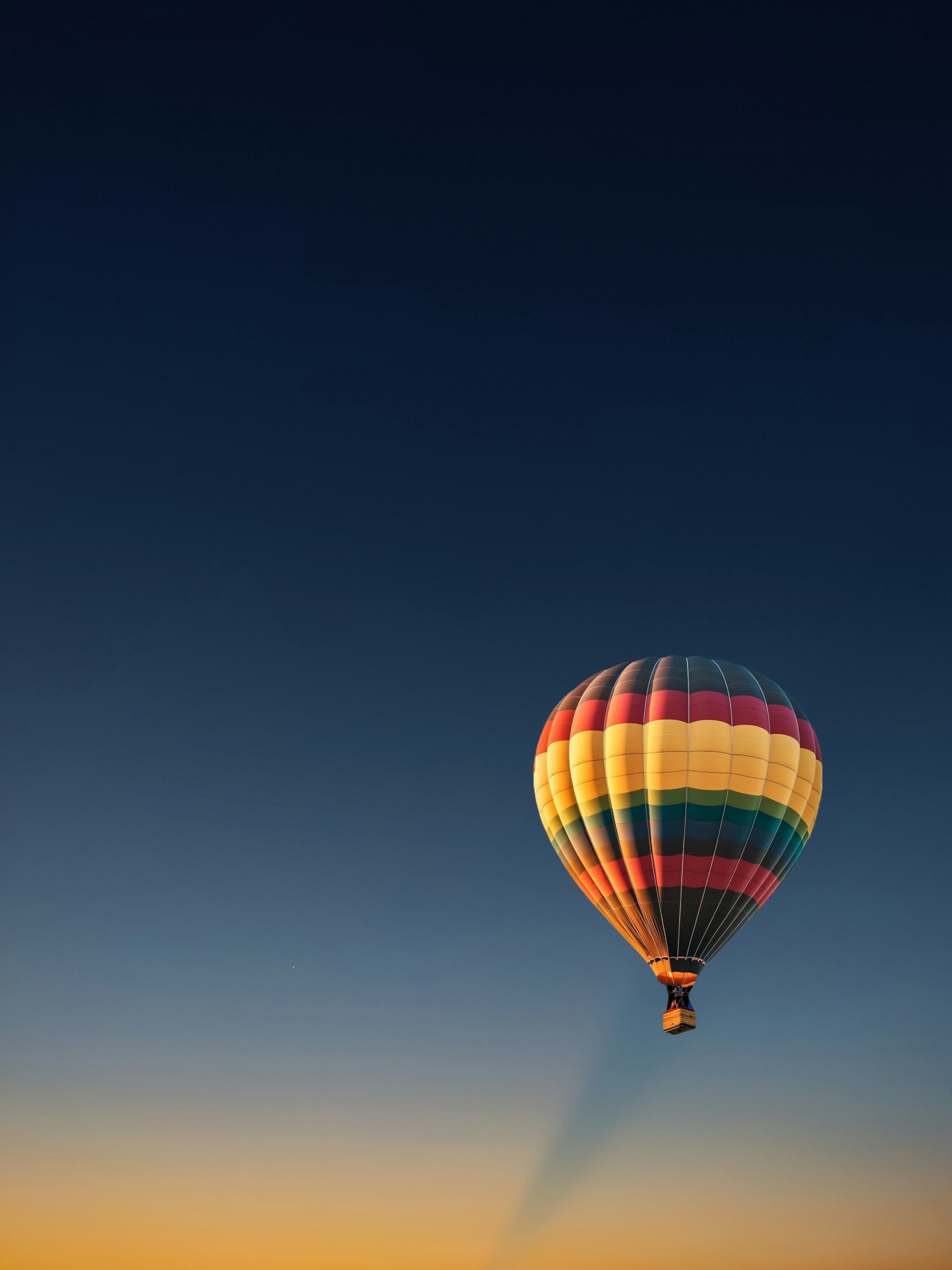 Above the Orange Horizon: A Striped Balloon Drifts into the Dusk