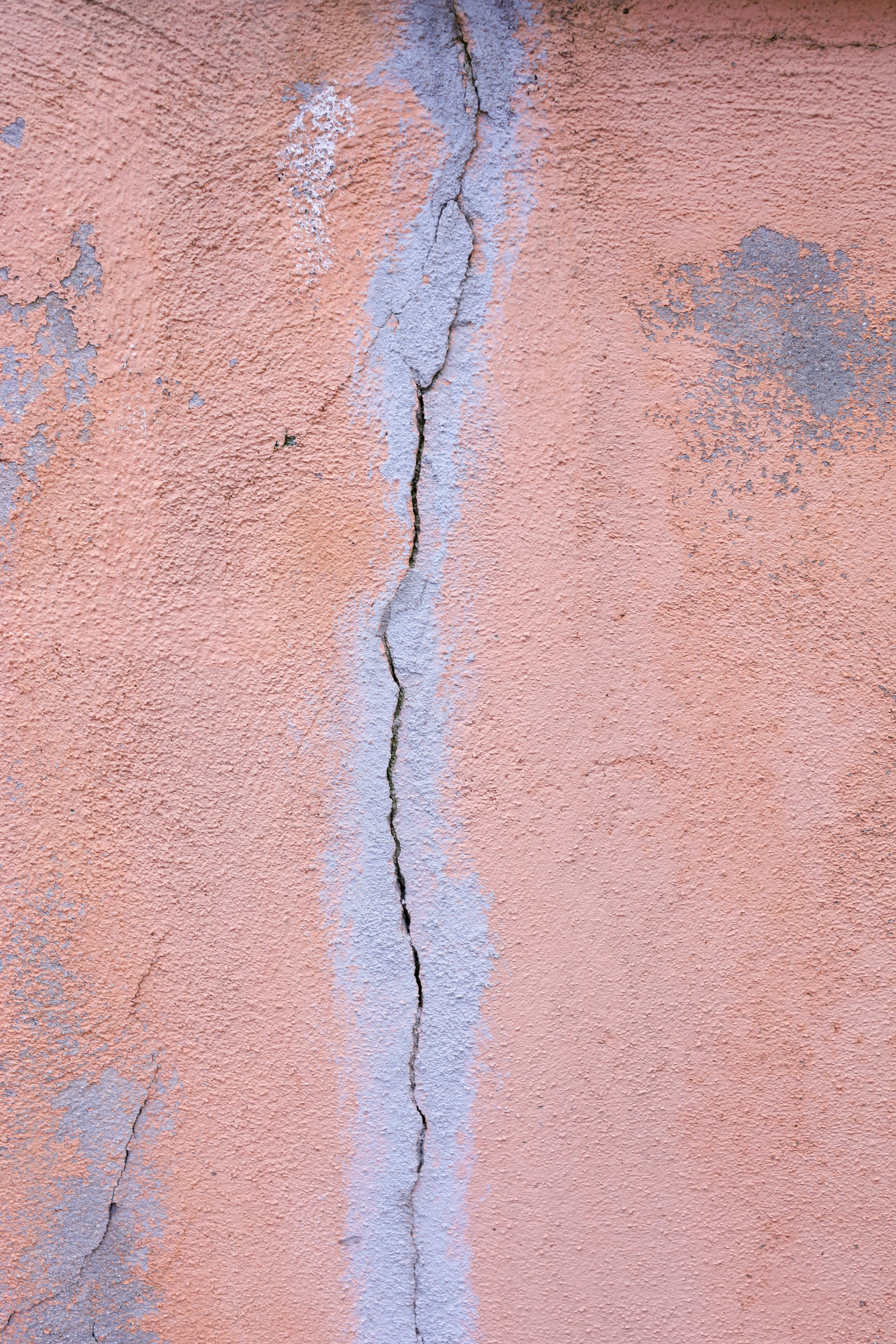 Cracked Wall Portrait: A Vertical Fault Line in Pink Plaster