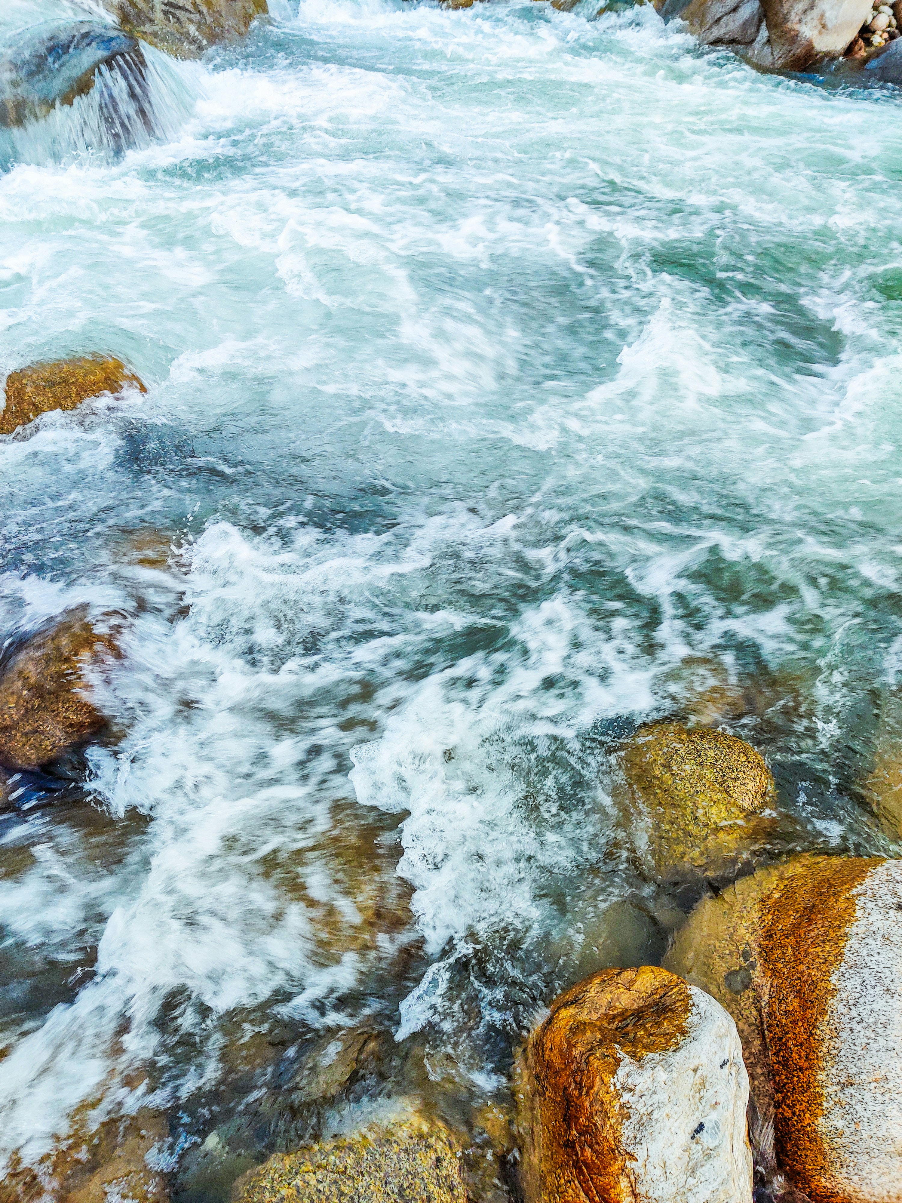 Cascading Turquoise Currents over Sunlit Rocks