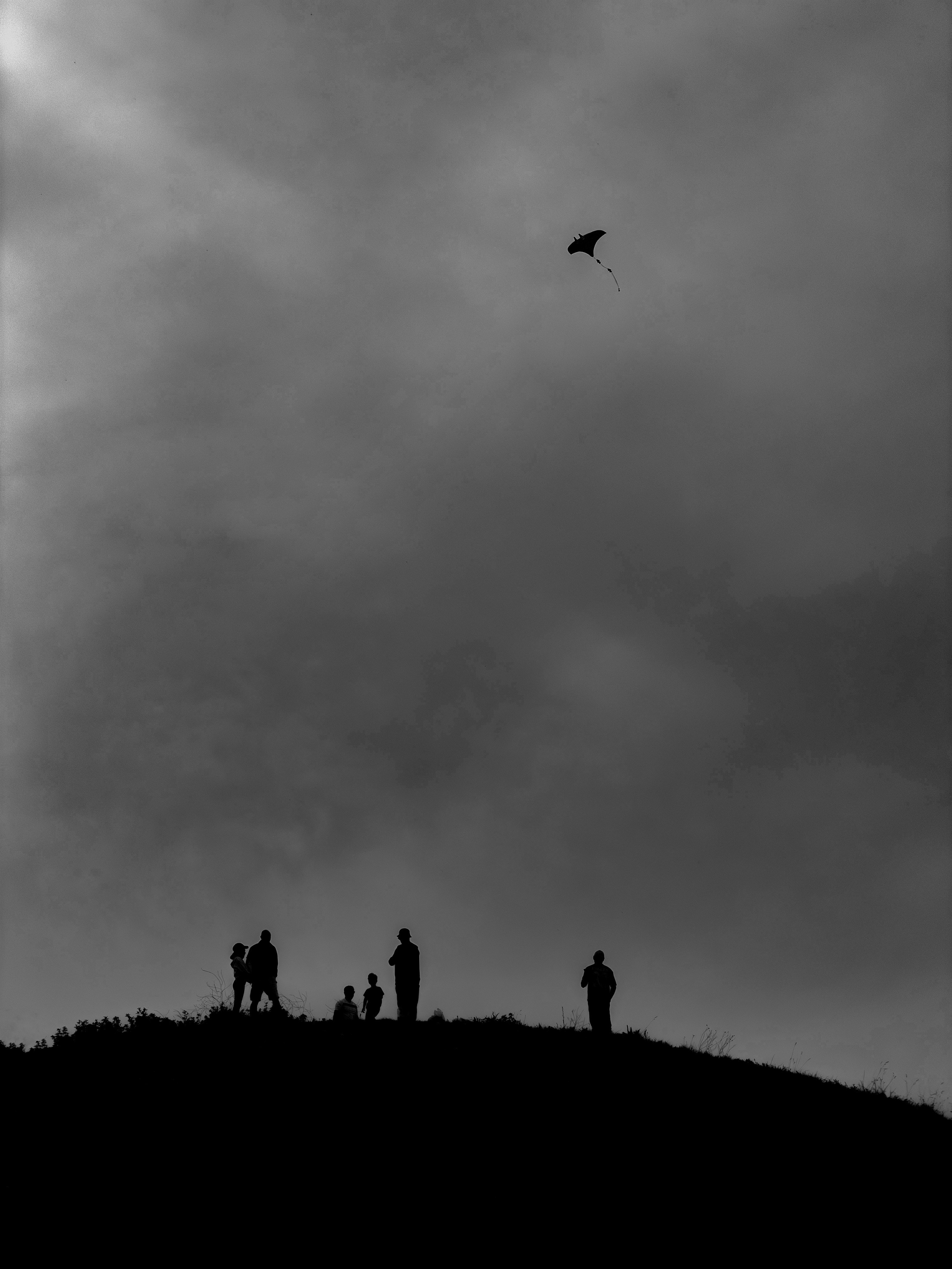 Silhouettes at the Edge: A Lone Figure and a Small Group on a Windy Hill