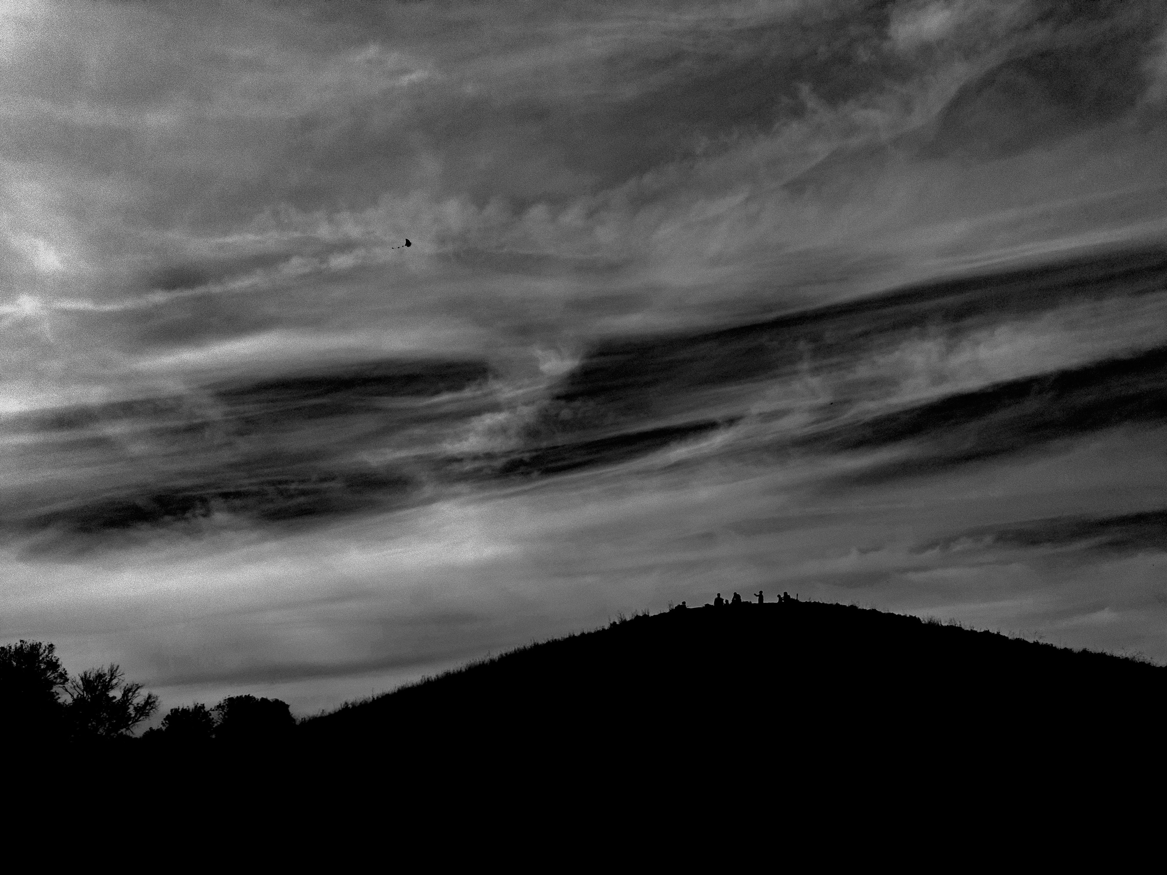 Silhouette over the Crest: A Quiet Horizon Under Dramatic Clouds