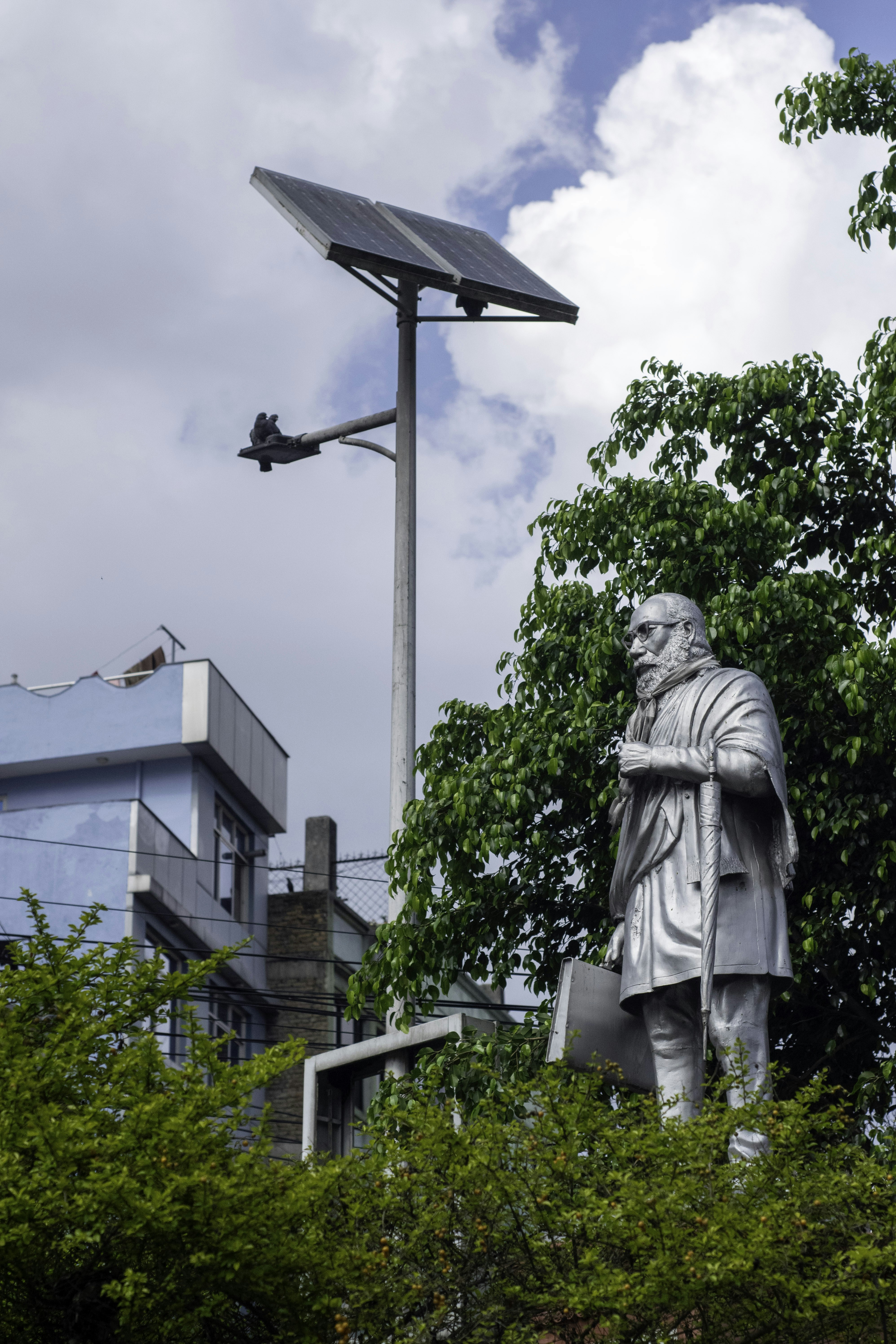 Metallic Sage: A Sculpted Figure Beneath the Solar Mast