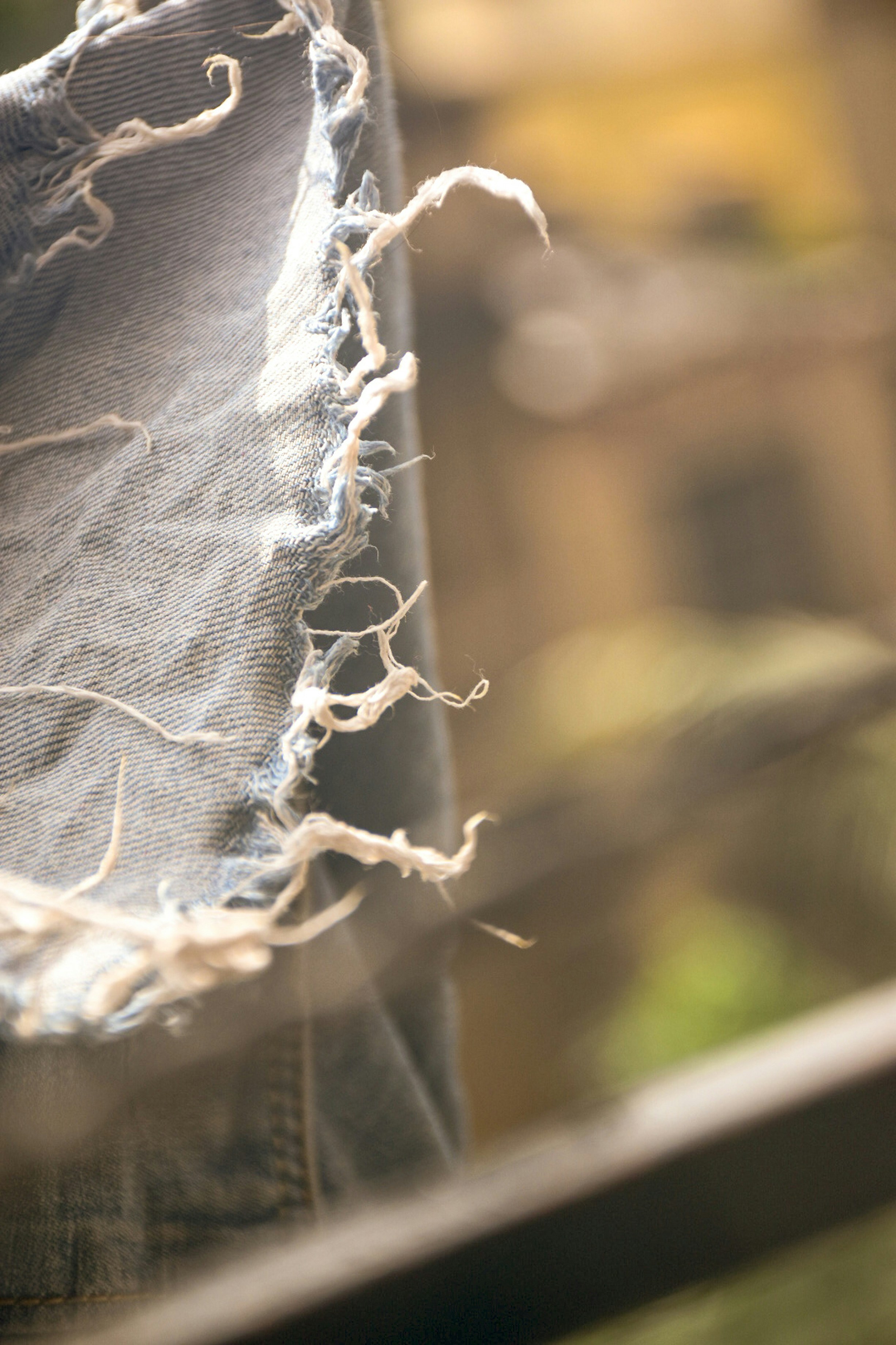 Frayed Boundary: A Close‑Up of Distressed Denim Adrift in Soft Light