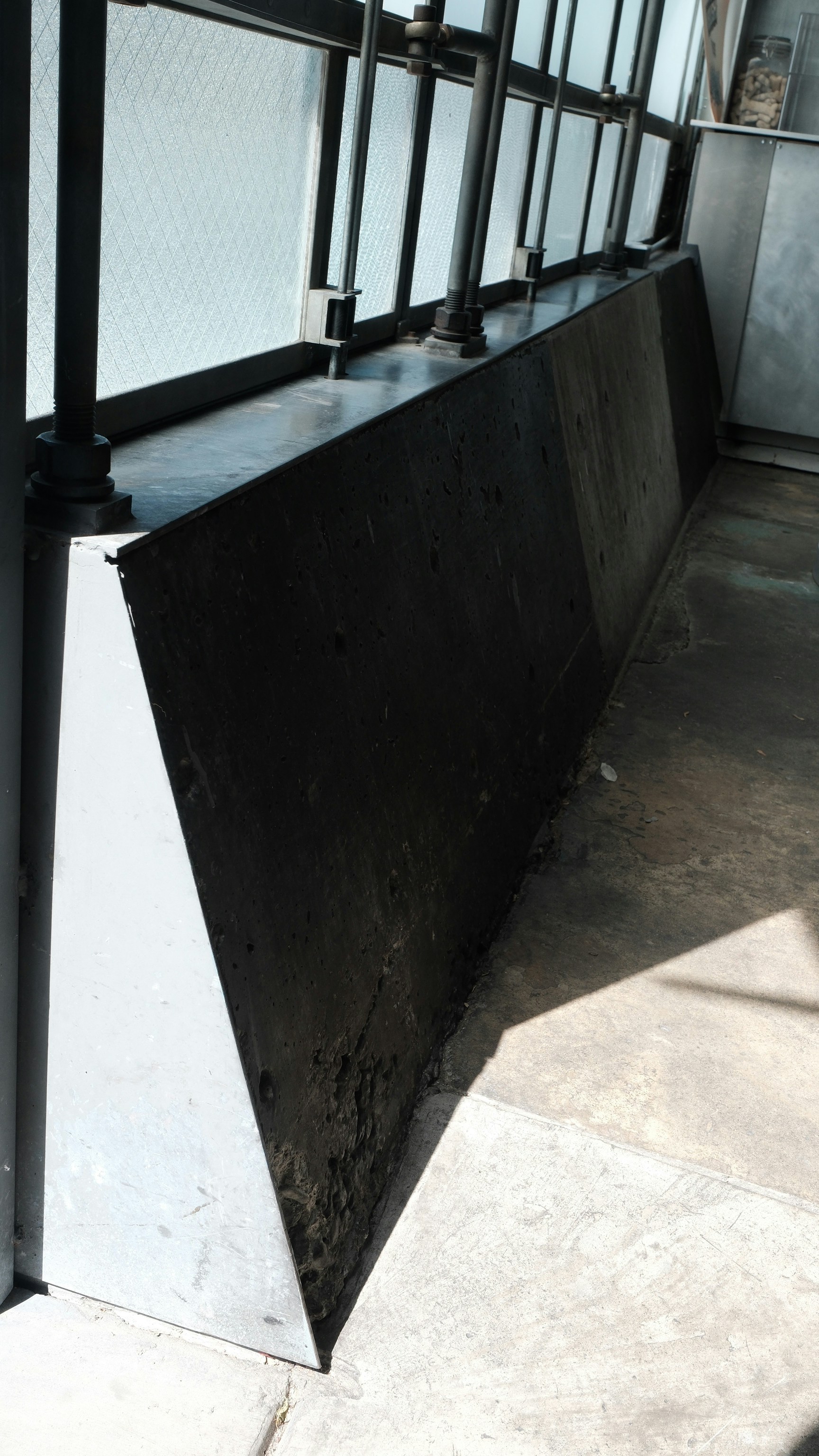 Industrial barrier against a sunlit sidewalk