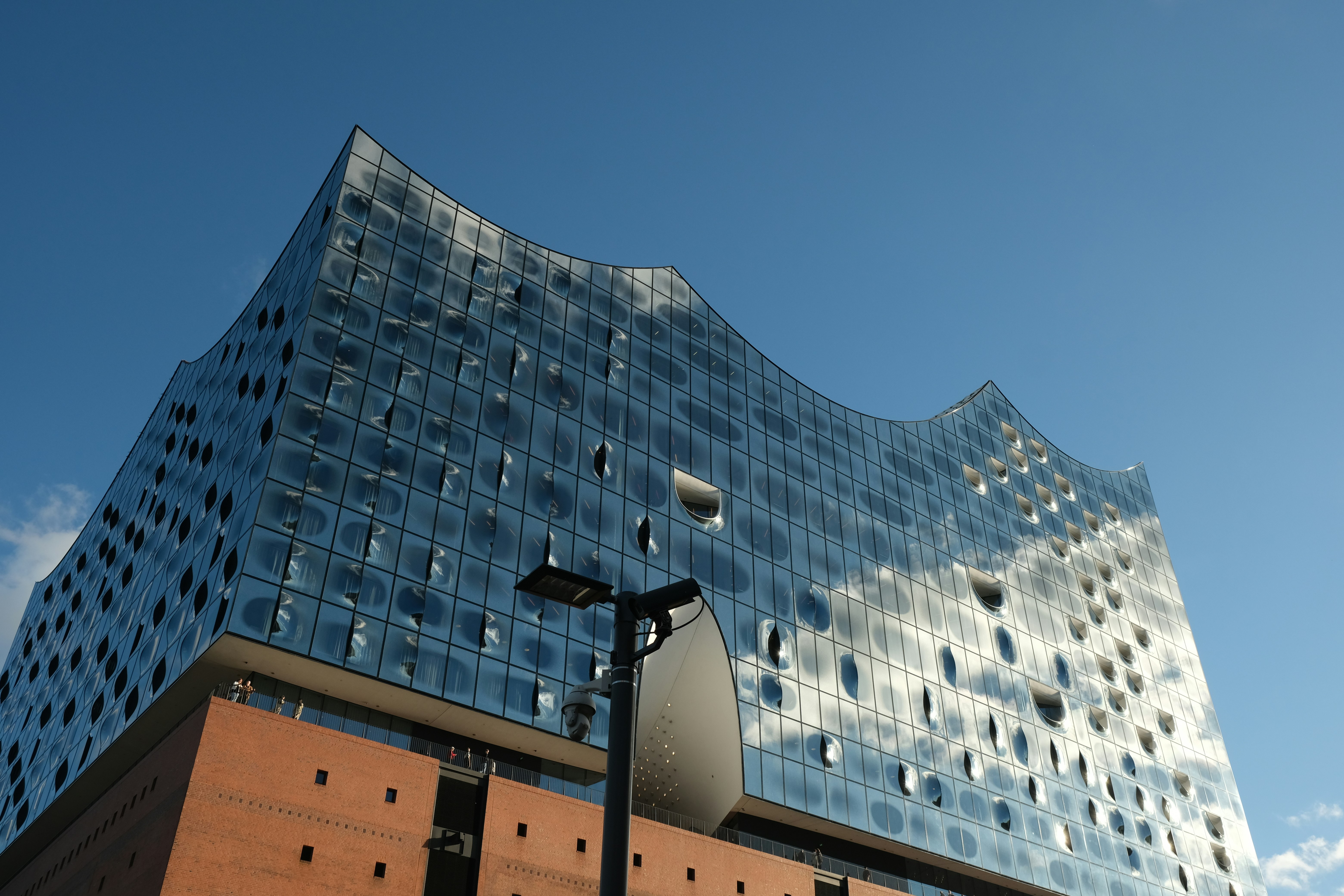 Shifting Facade: A Glass Curve Above Brick and Streetlamp