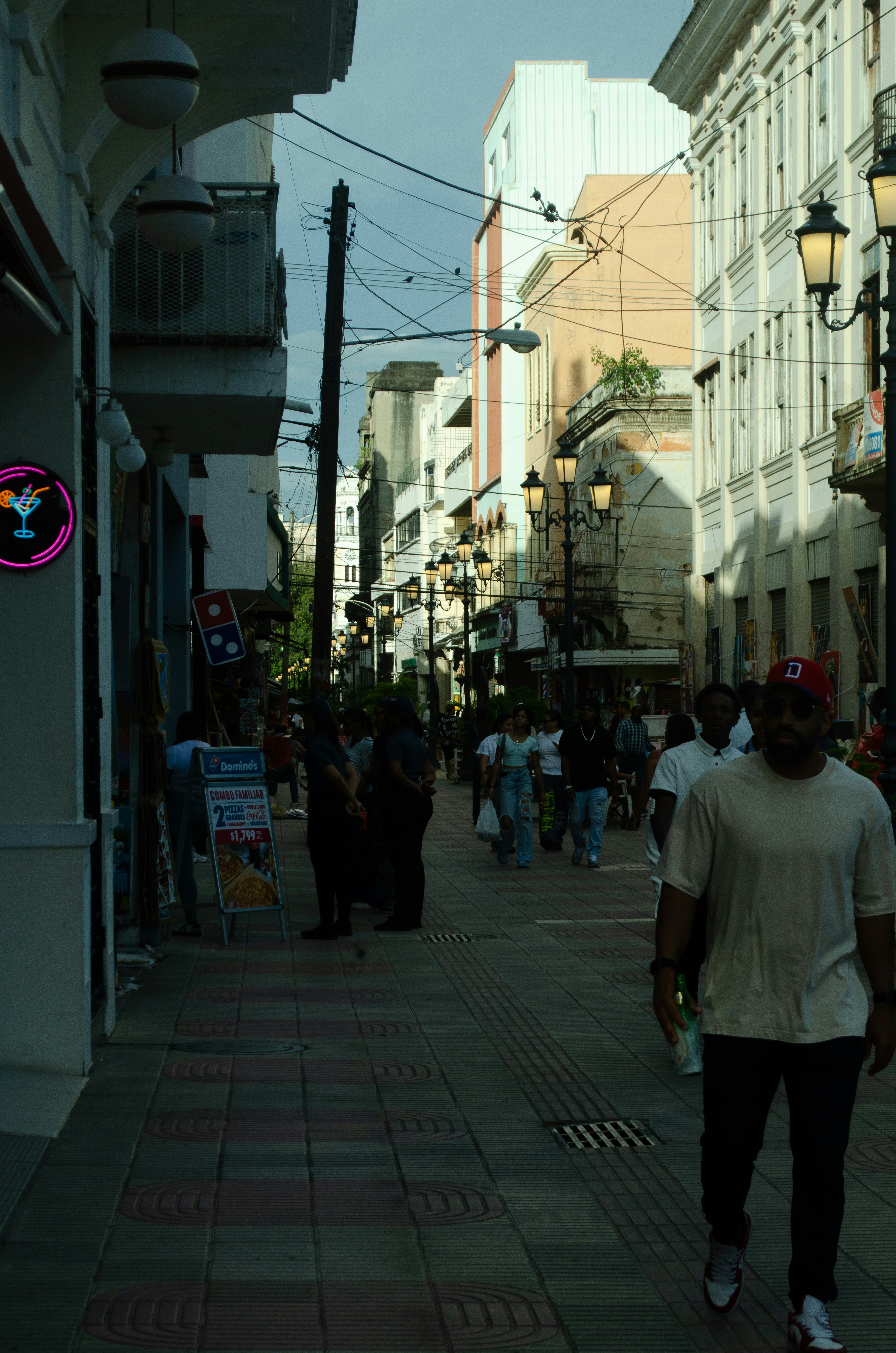 People-filled Calle Principal: A Shuttered Pulse Through a Bright Corridor