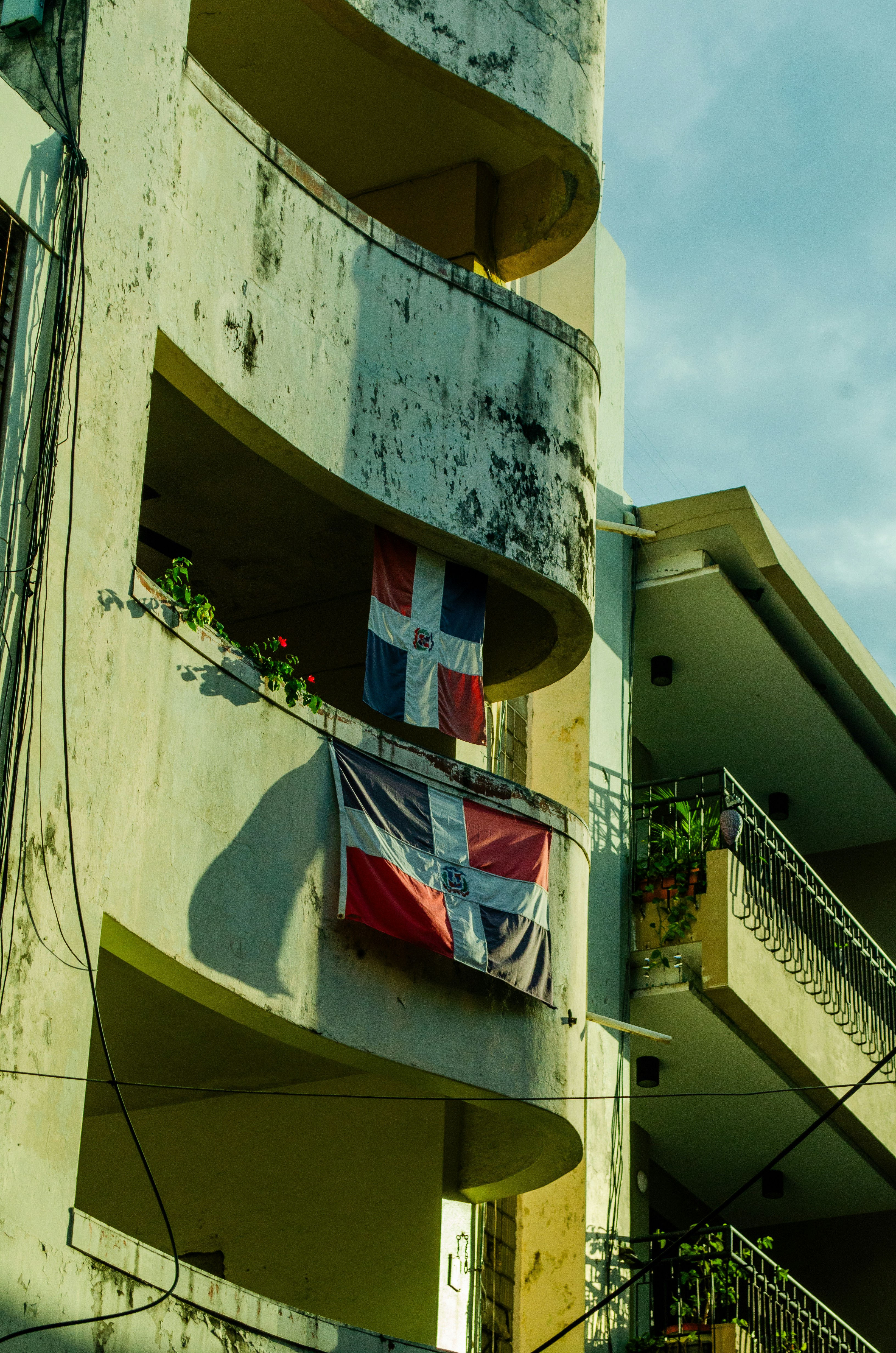 Flags Drape the Curved Concrete: A Balconied Quiet in Sunlit Decay