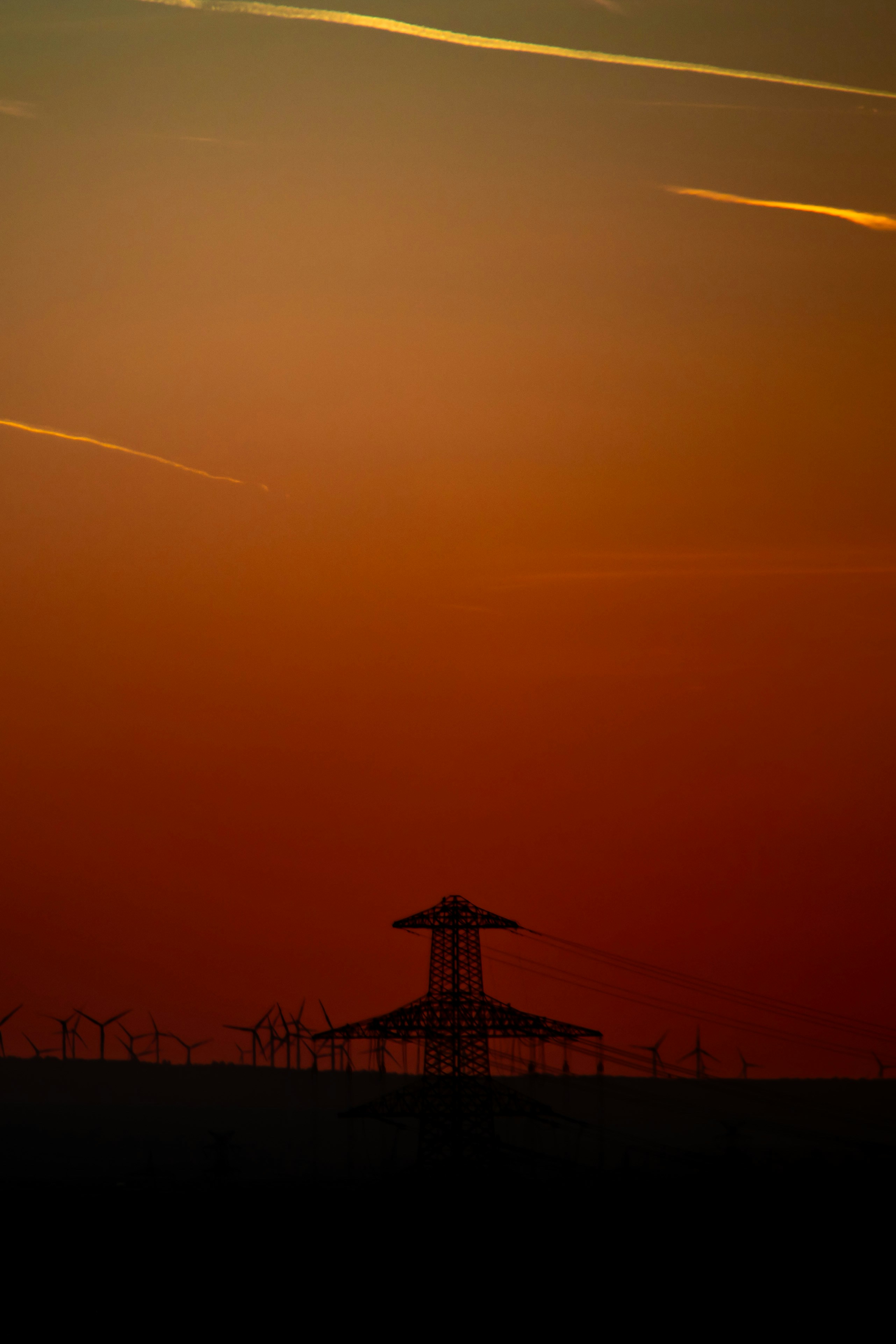 Silhouette at Dusk: Transmission Towers Against a Fiery Horizon