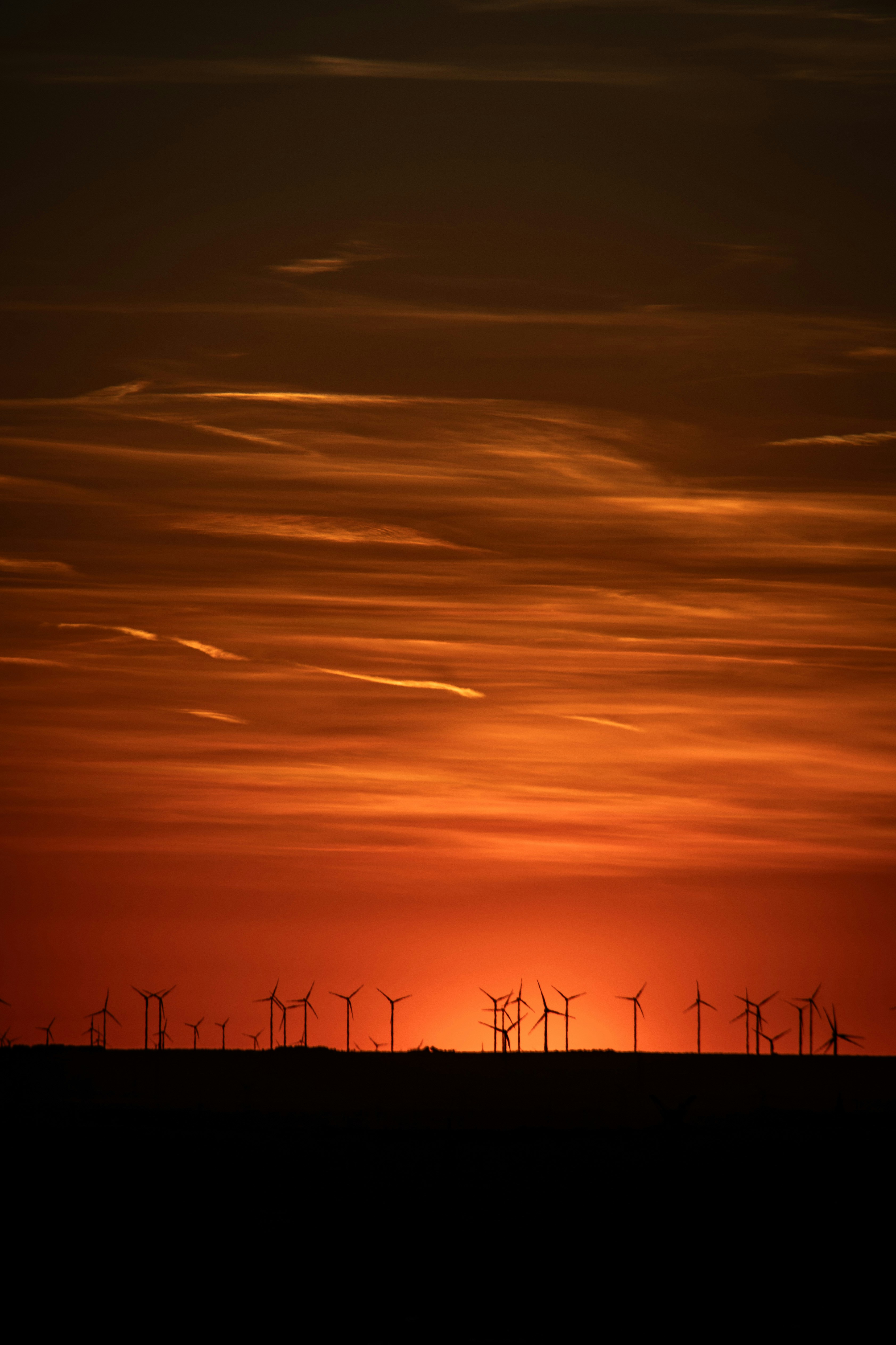 Silhouette of Wind Turbines at a Fiery Horizon