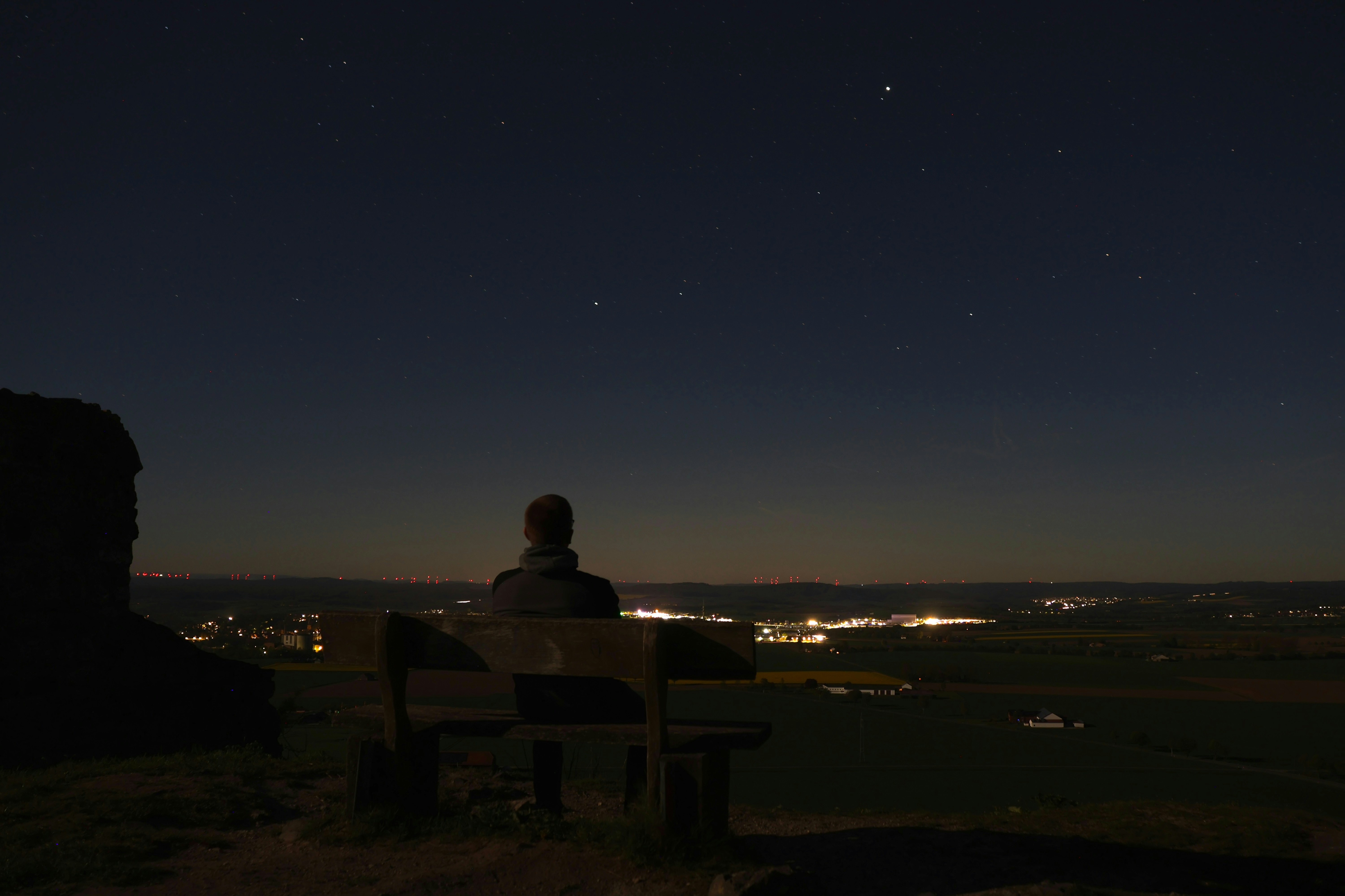 Night on the Hill: A Lone Figure Beneath the Star-Studded Sky