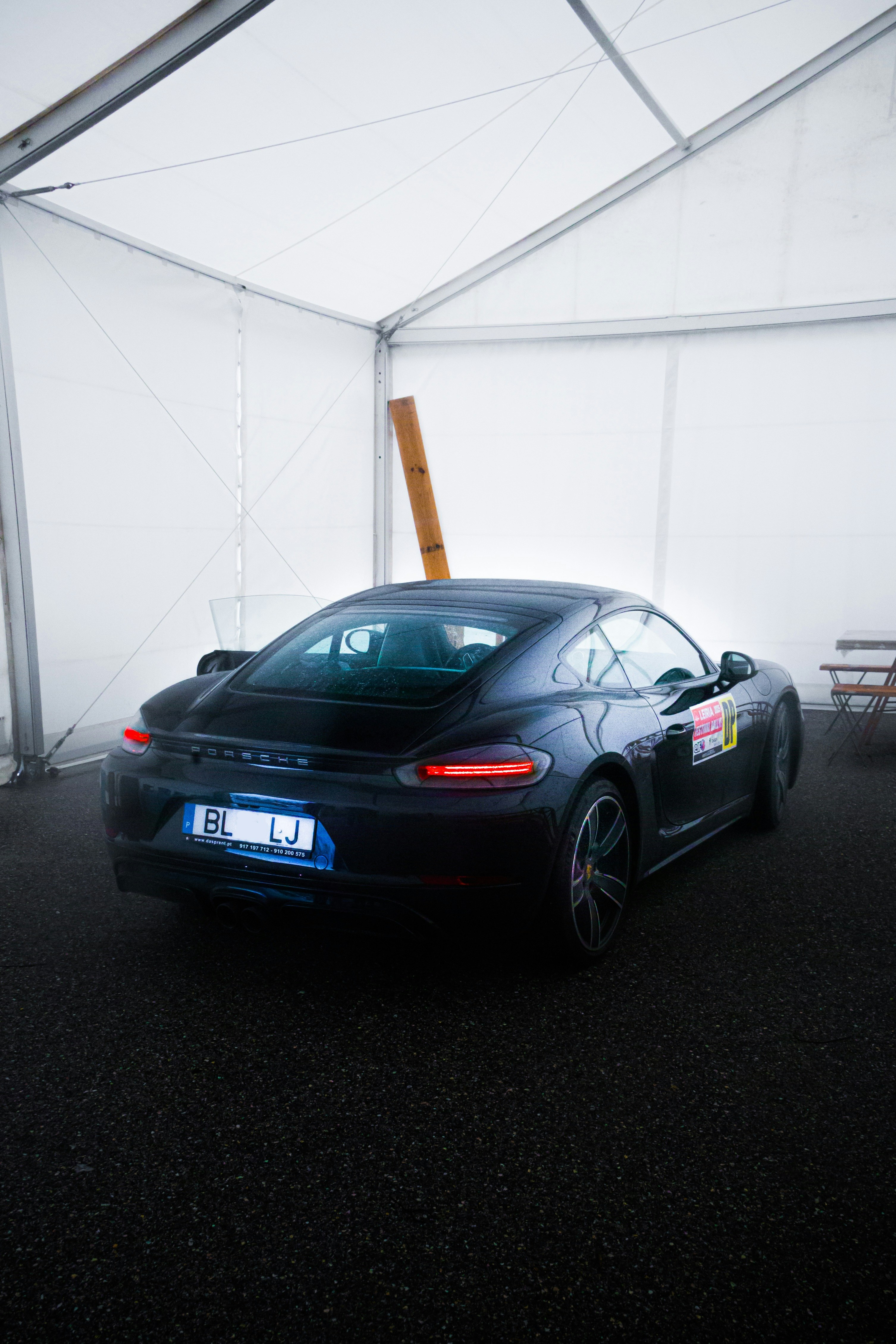 Dark Porsche under a White Canopy: A Car on Display