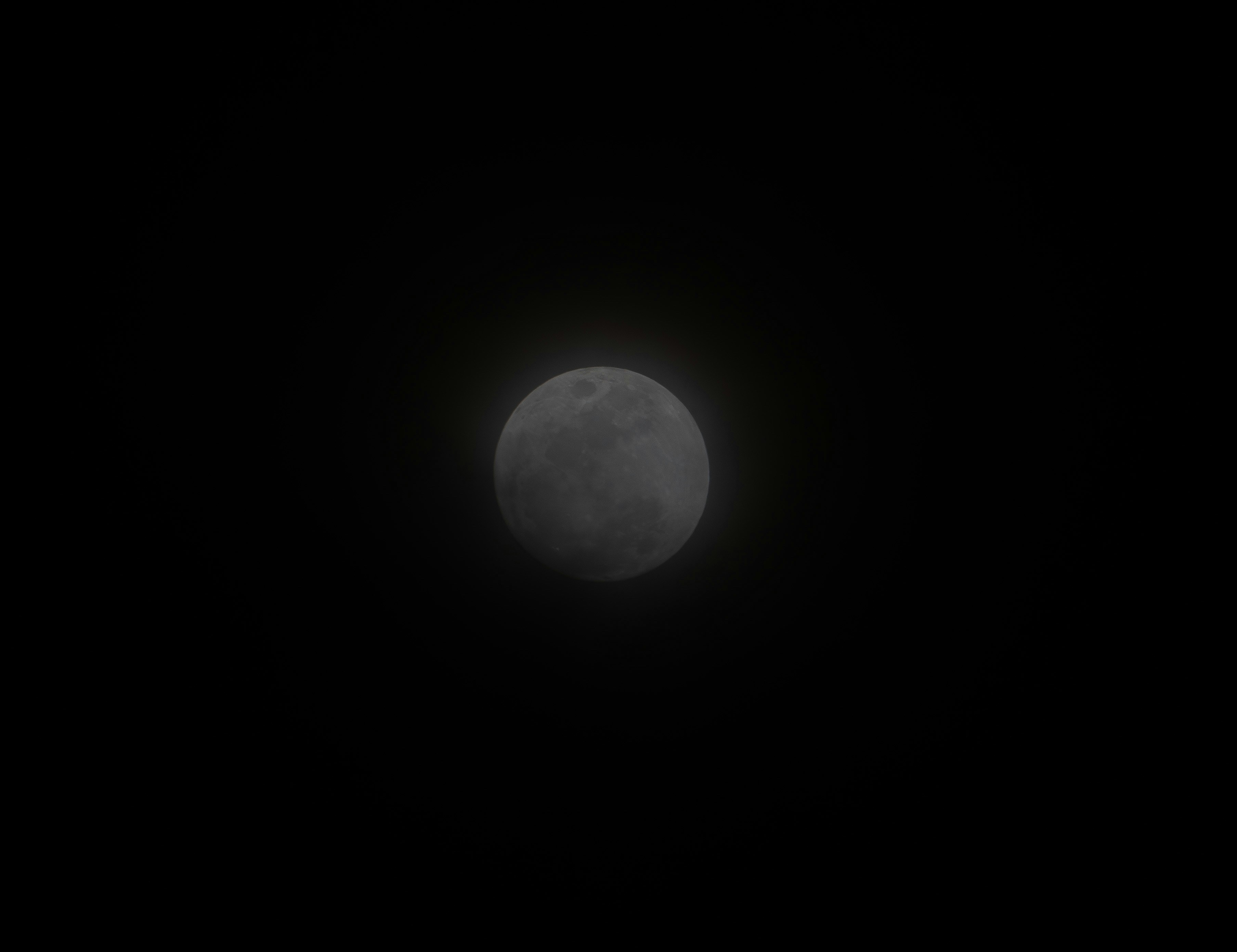 Moonrise in the Void: Subtle Lunar Glow Behind Darkness