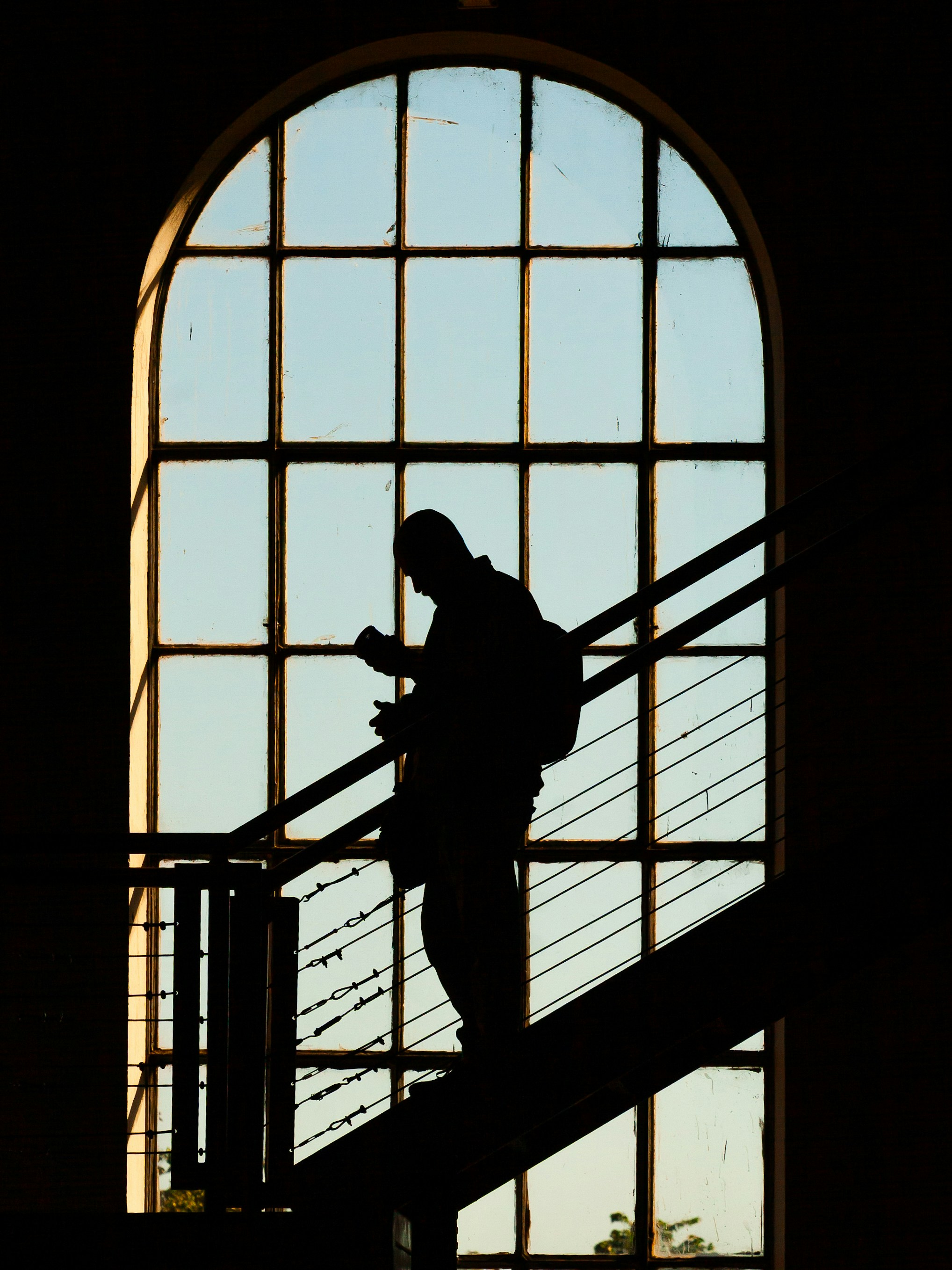 Silhouette on the Staircase: A Figure in Front of a Broad Window Grid