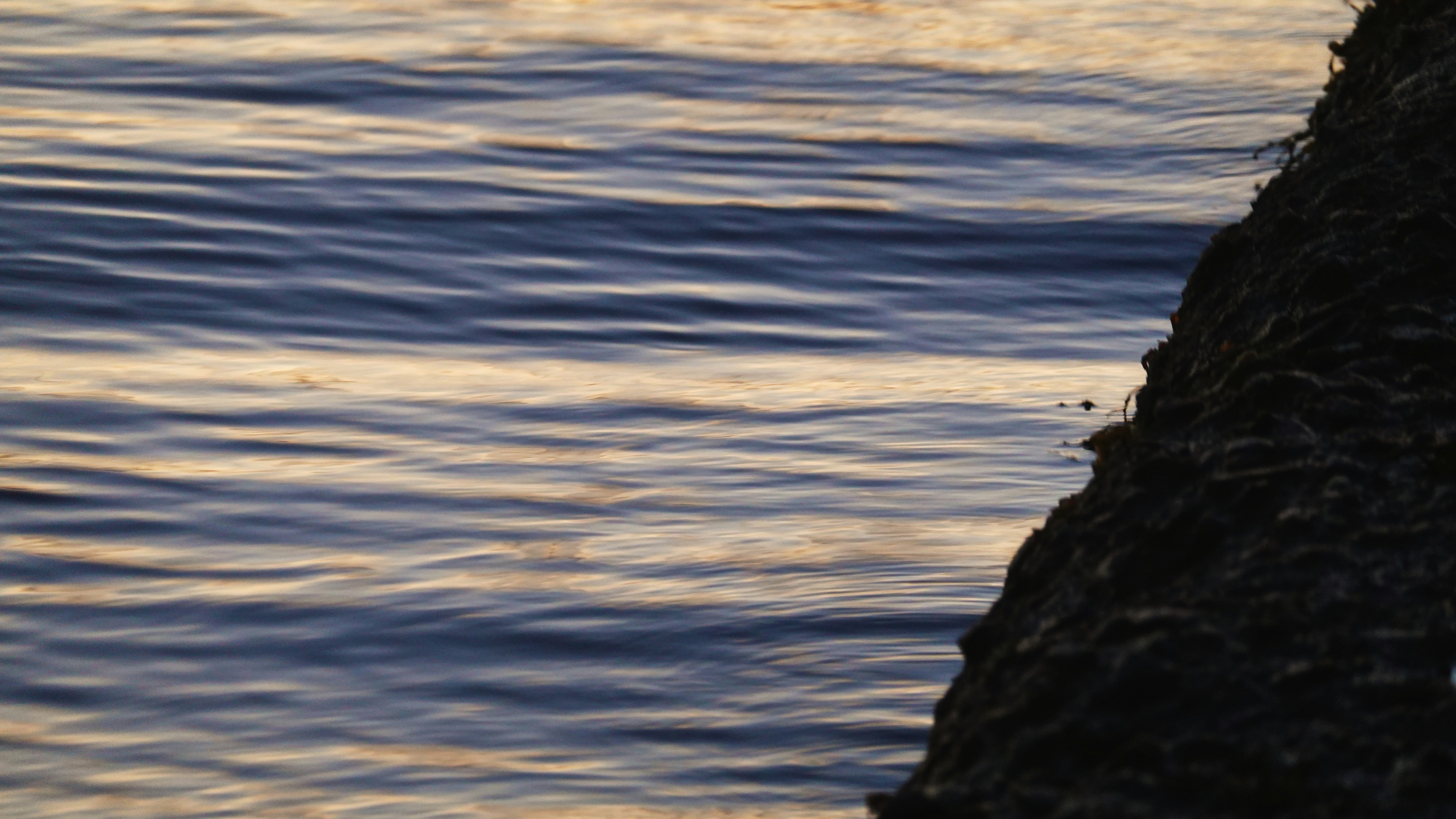 Rippling water surface with dark rock edge
