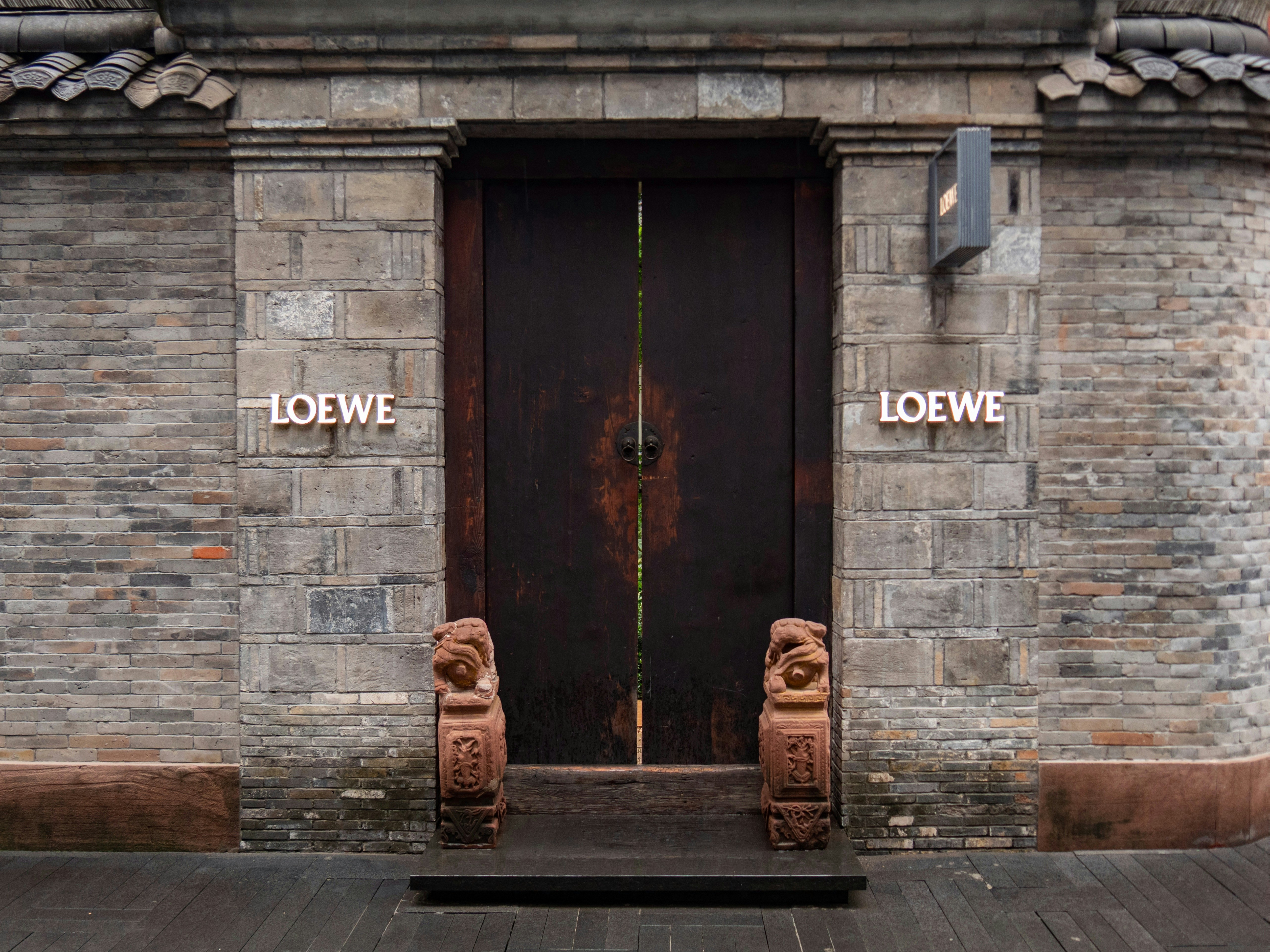 Twin LOEWE Doors: A Stoic Entrance Framed by Weathered Brick
