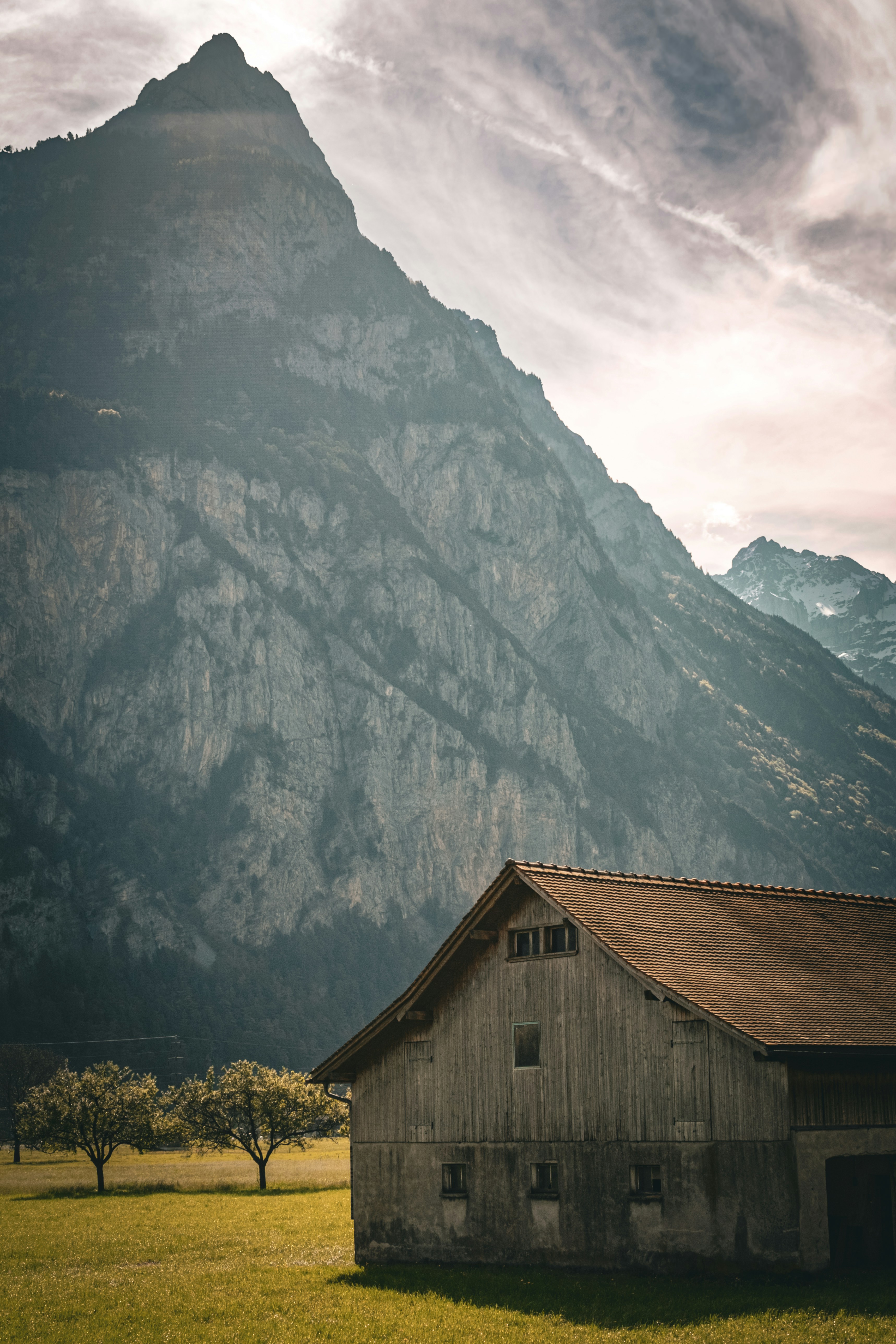 Rustic Barn at the Foot of a Towering Alpine Face
