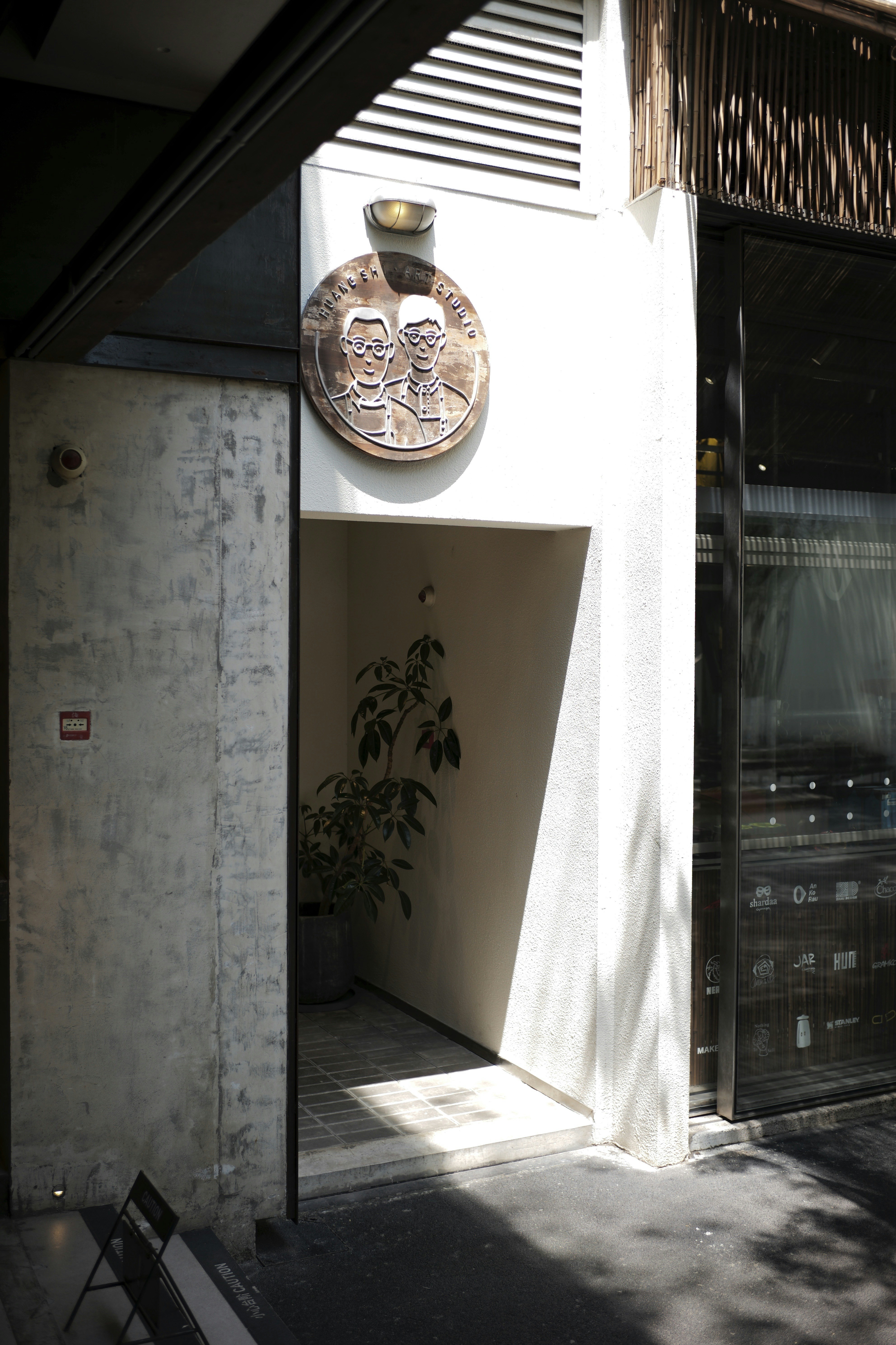 Entrance under a round sign: two masked figures above a quiet corridor