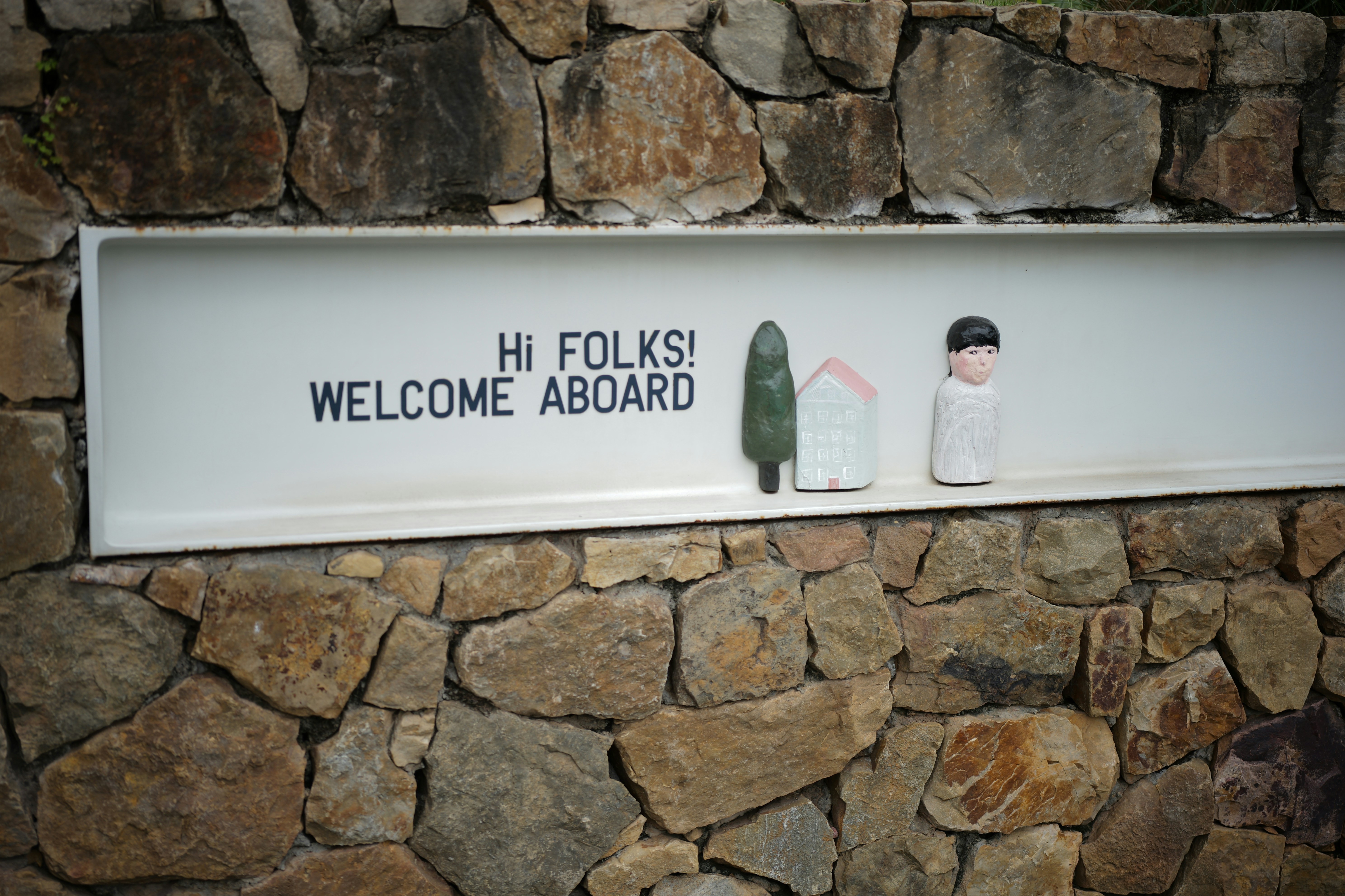 Welcome Aboard Sign with Tiny Sculptures on a Stone Wall