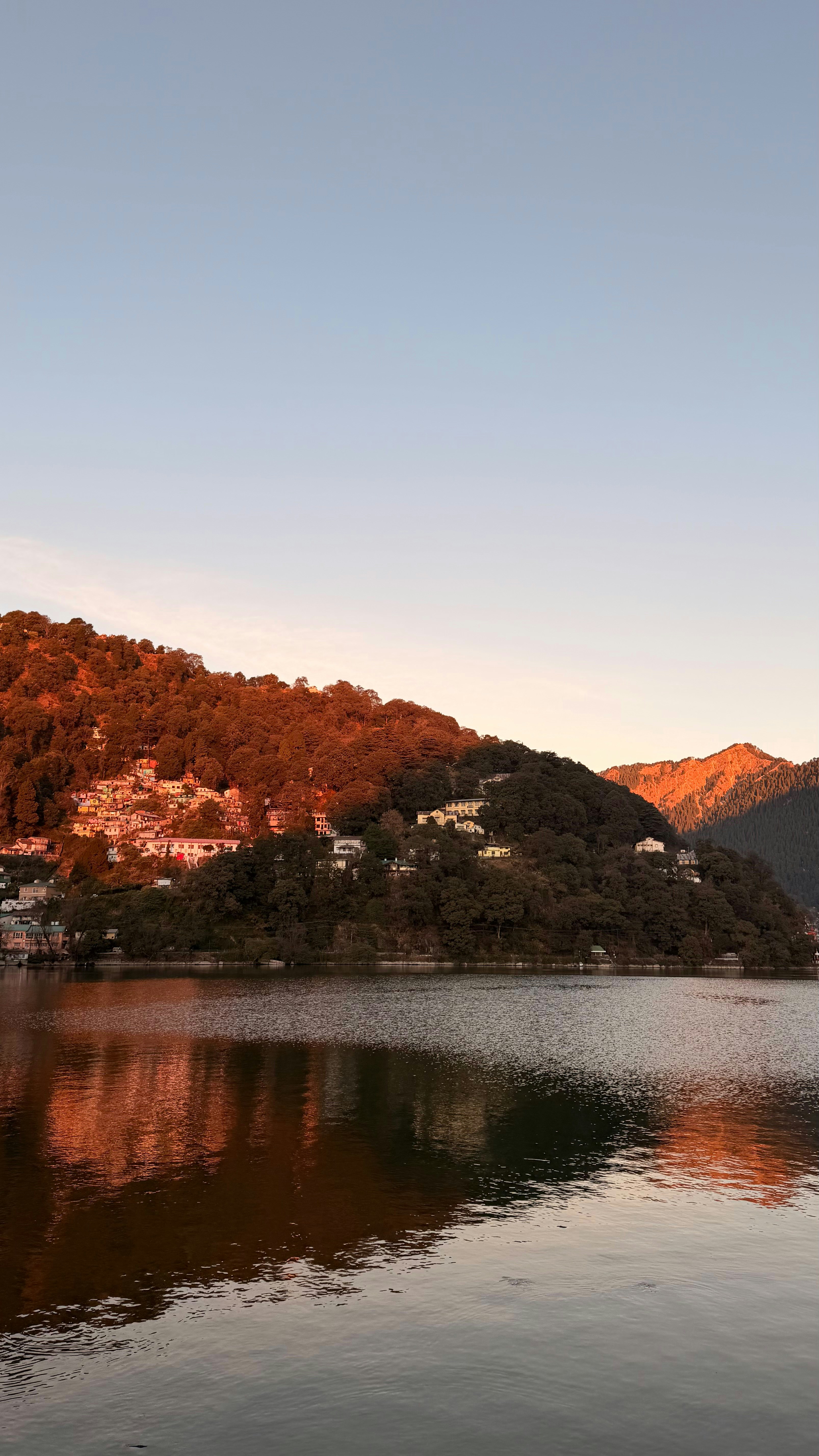 Sunset on the hillside village by the tranquil lake