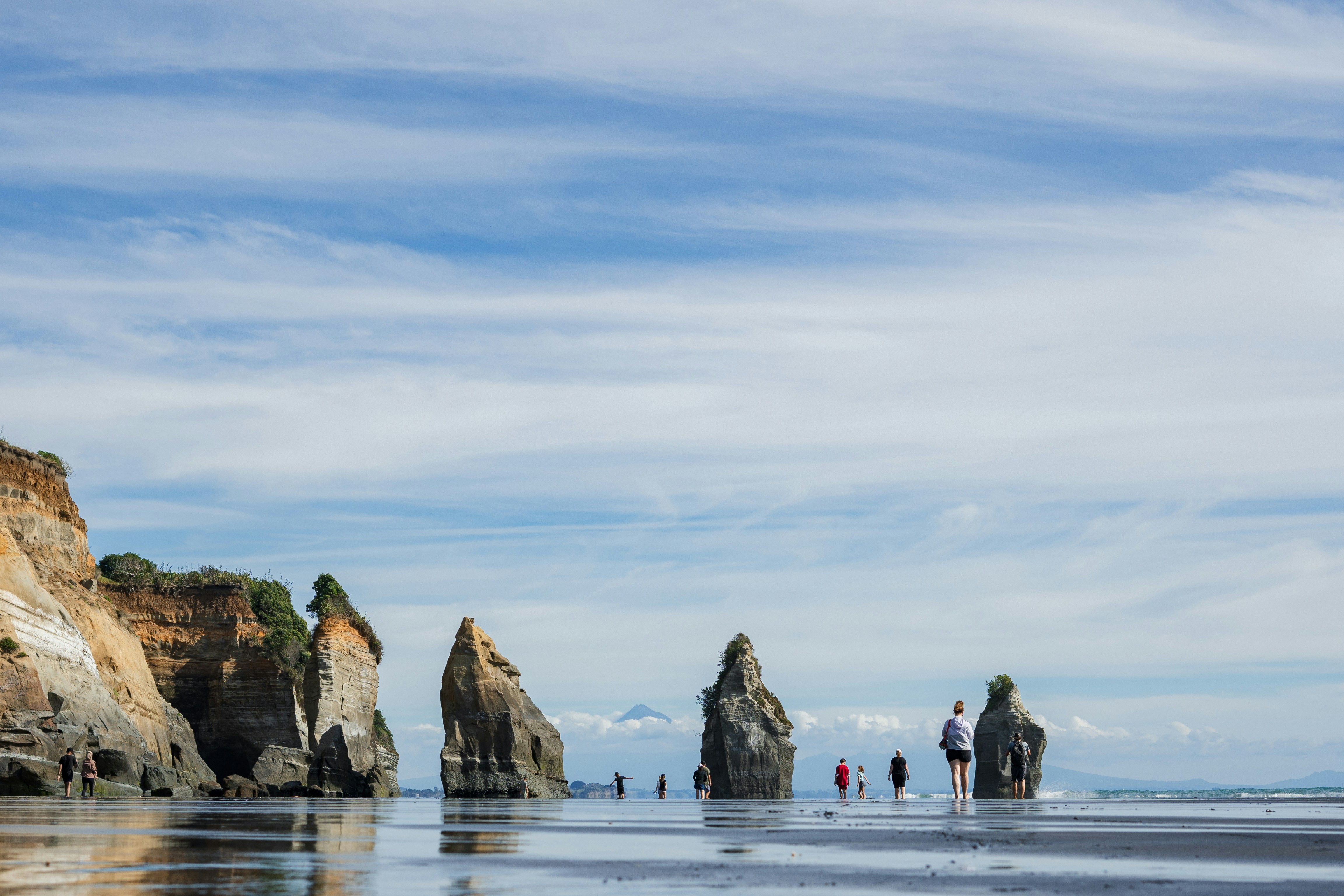 Sea-stack silhouettes at low tide under a spanned blue sky