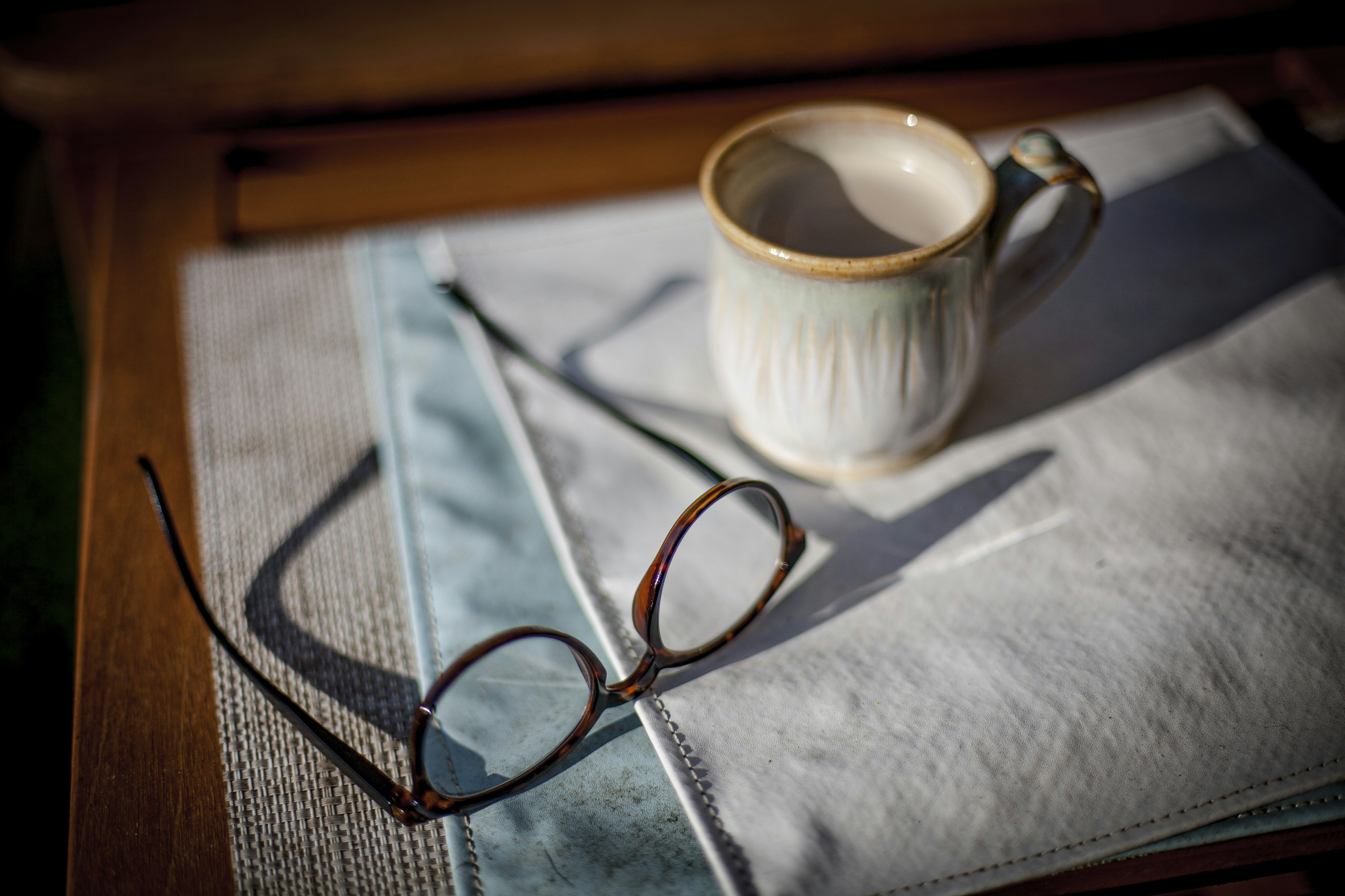 Quiet Study Moment: Glasses Rest on a Linen Surface Beside a Ceramic Mug