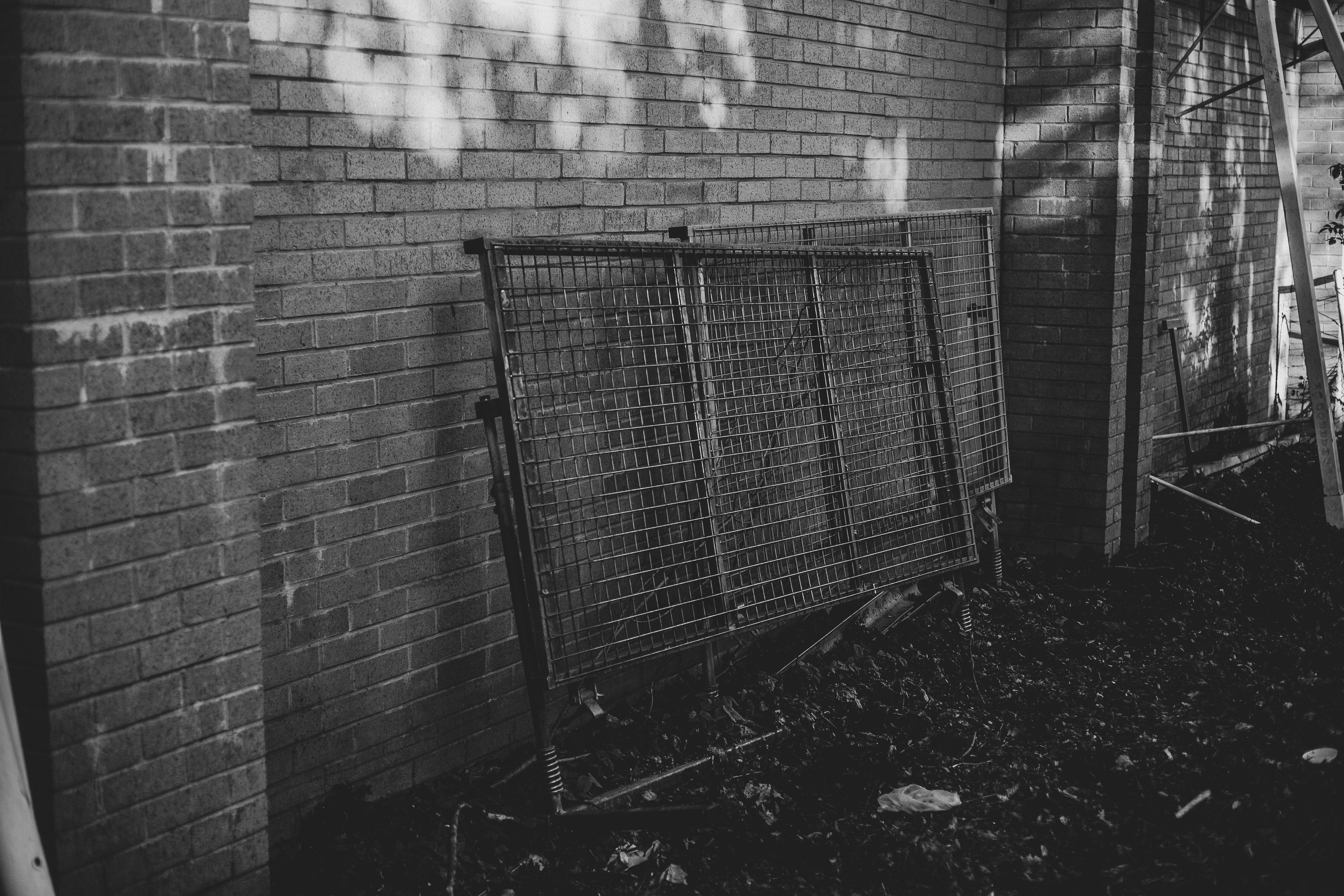 Disused alleyway fence leaning against a graffiti'd brick wall