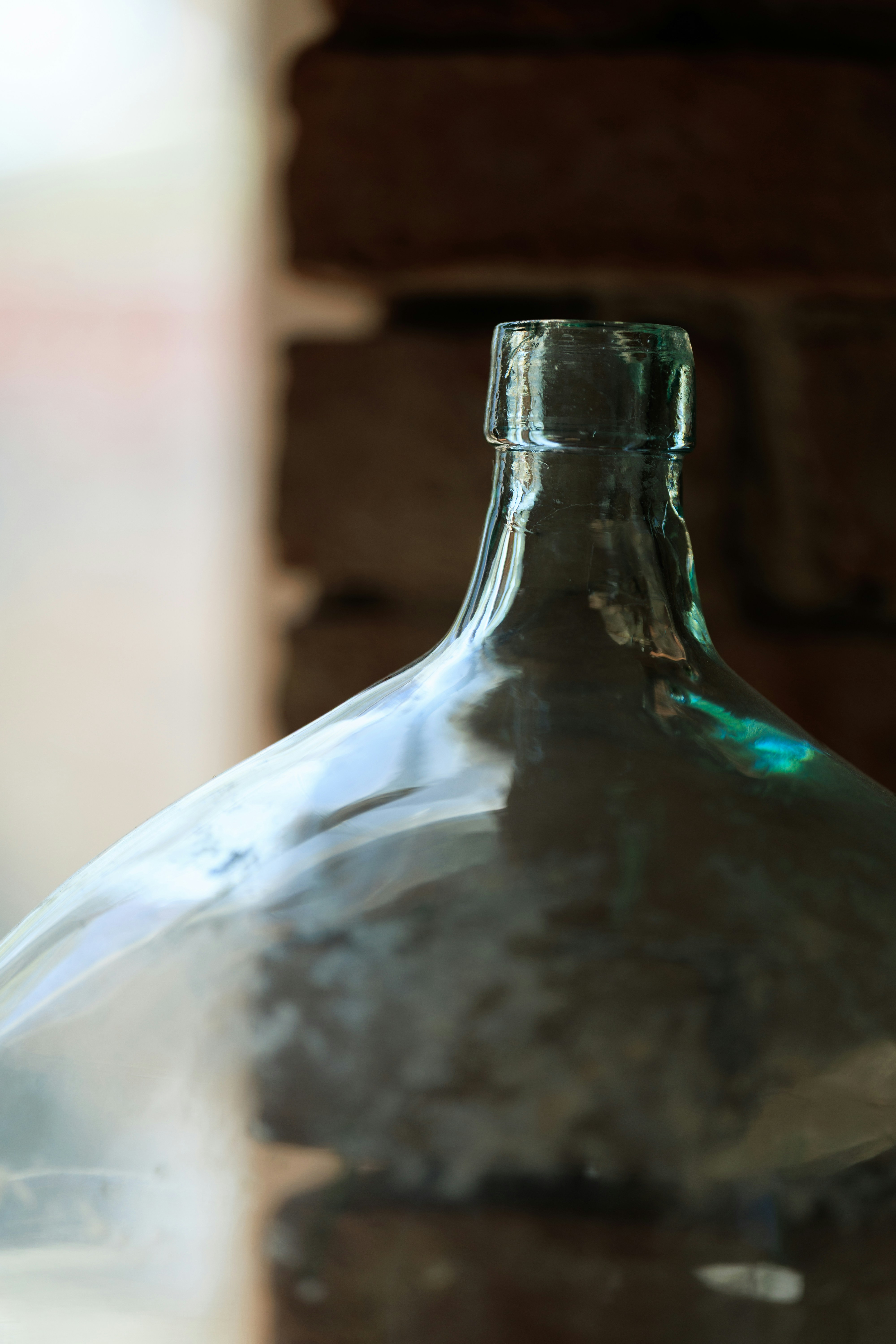 Glassy Narrow Neck: A Close-Up of a Vintage Bottle Against a Brick Backdrop