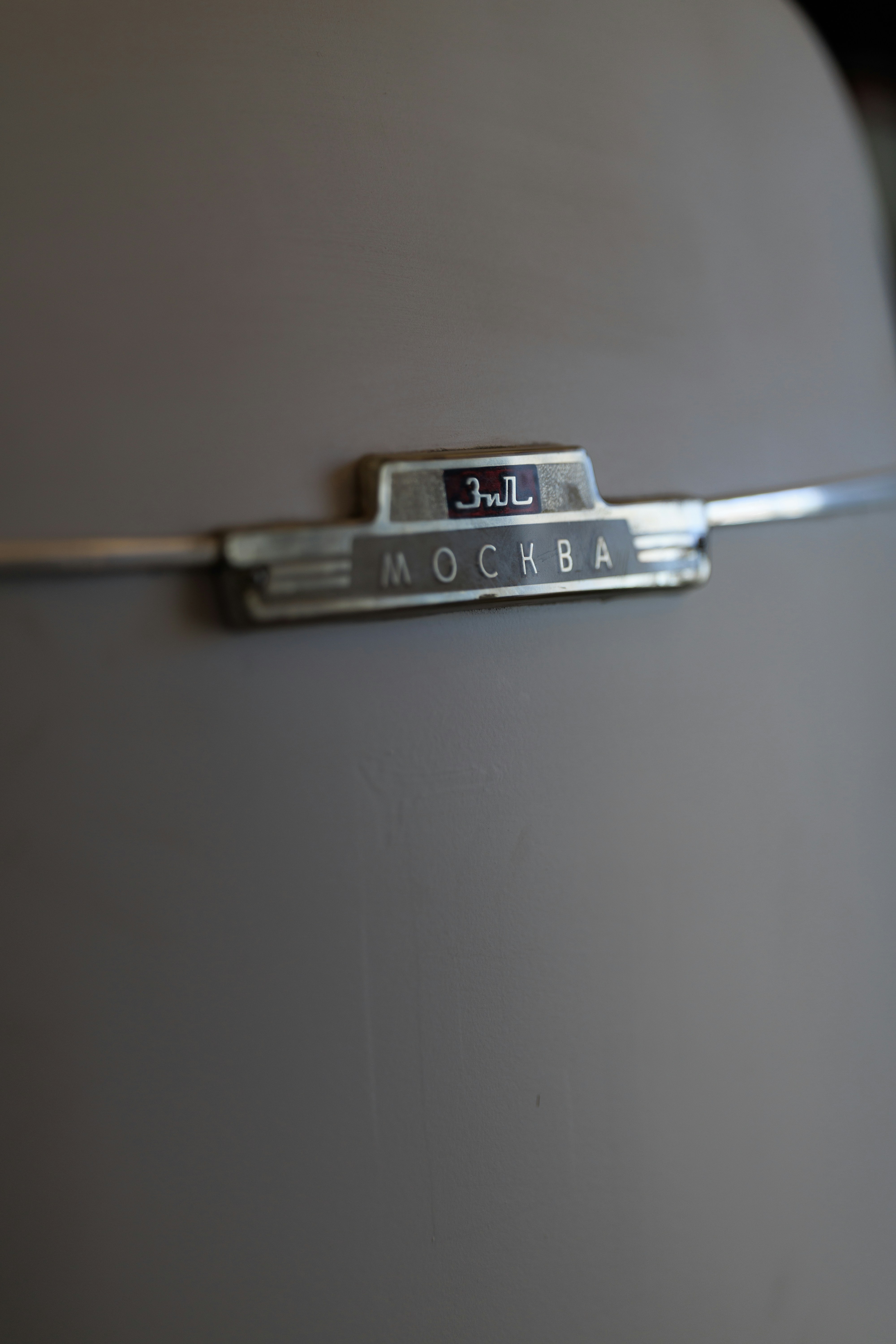 Metallic emblem on a smooth taupe surface: a vintage latch reading 'MOCKBA'