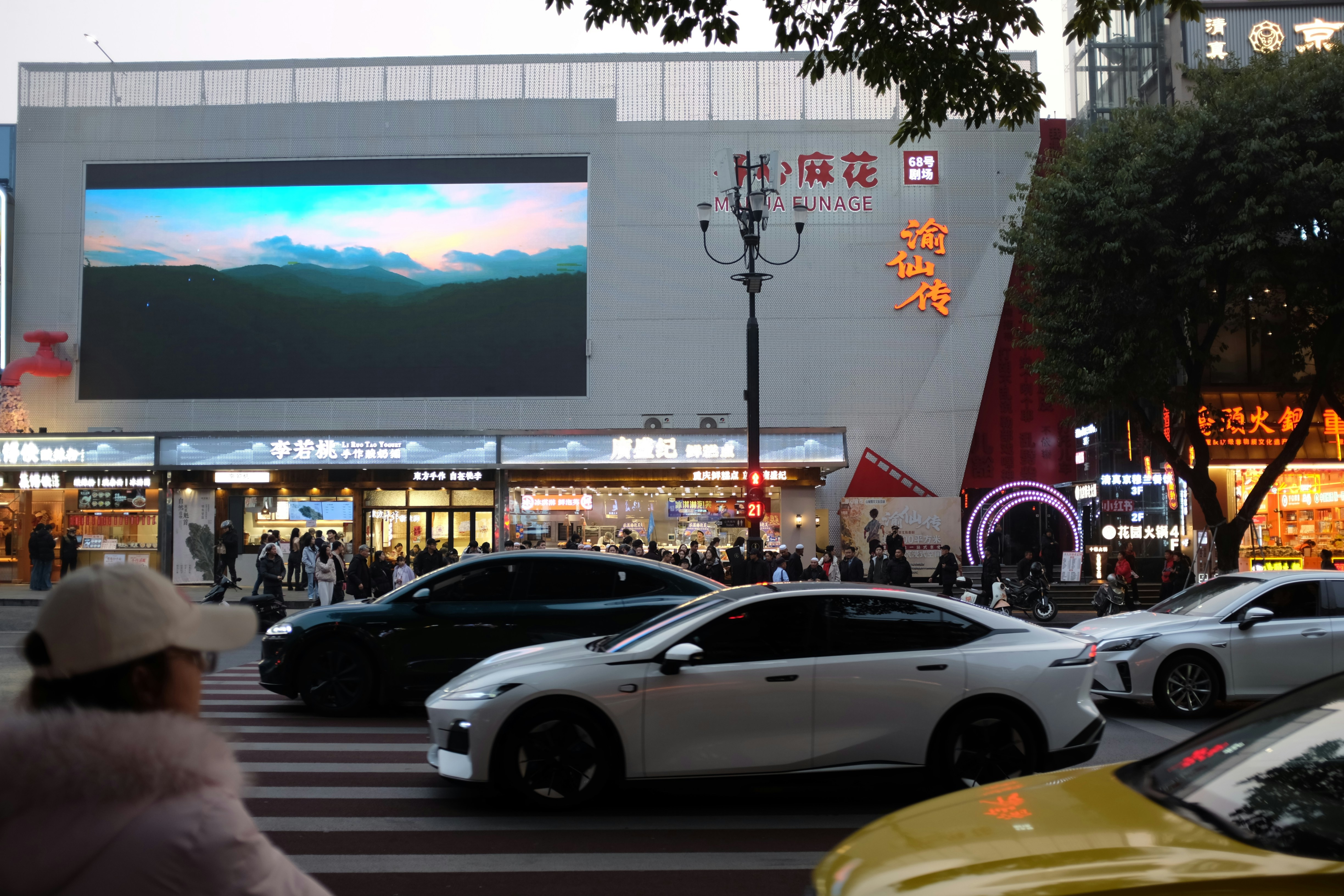 Urban Night: Neon Signage and Streamlined Traffic in a Busy Mall District