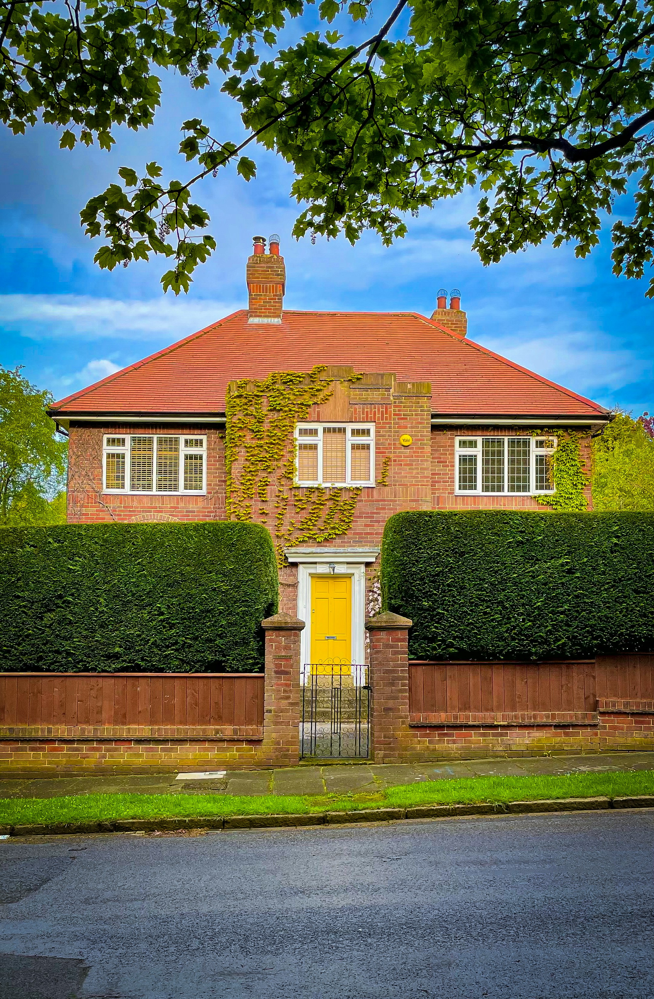 Sunlit Brick Cottage with Climbing Ivy and a Bright Yellow Door