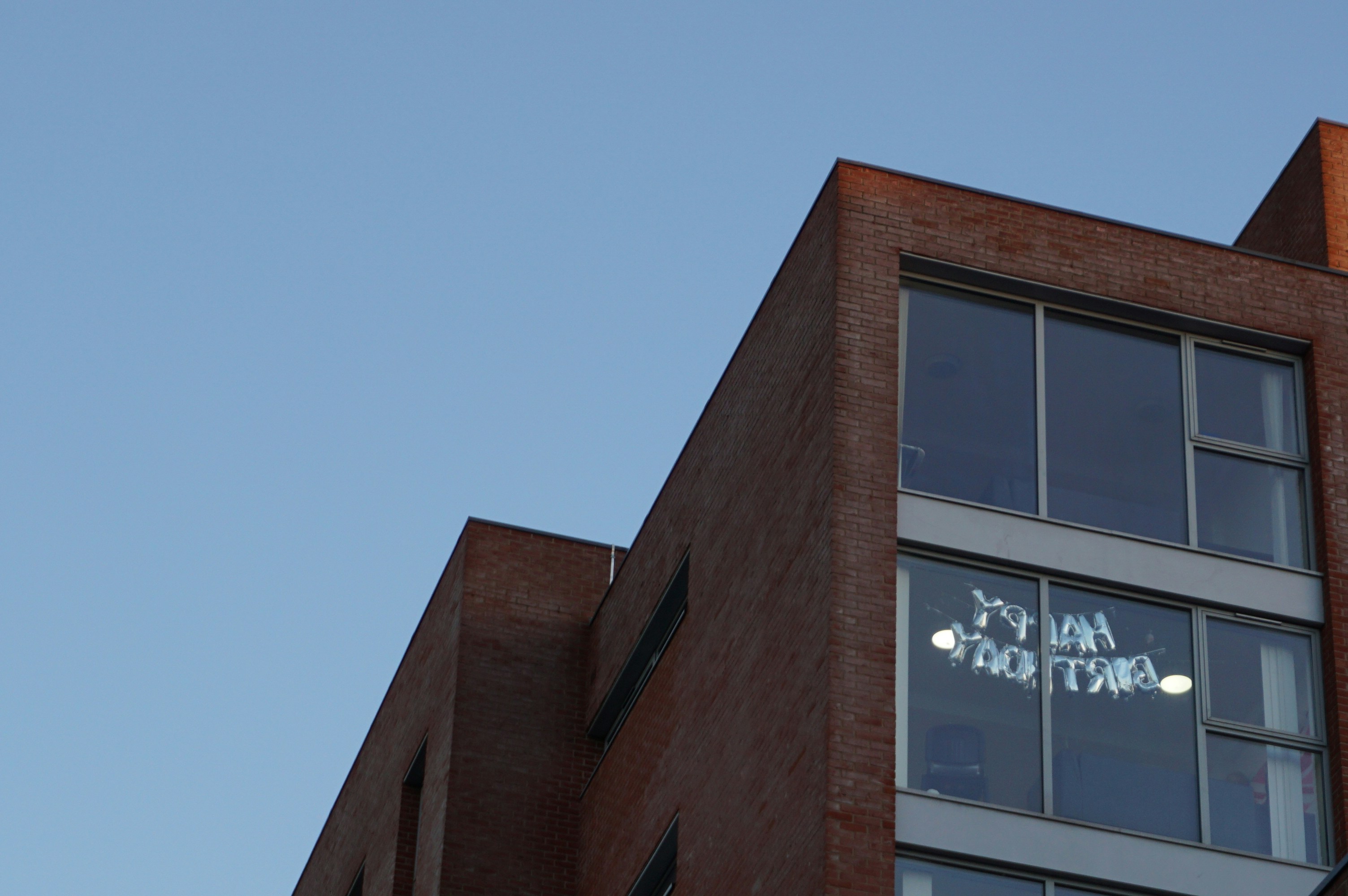 Brick Corner under a Clear Sky Reflects in Modern Windows
