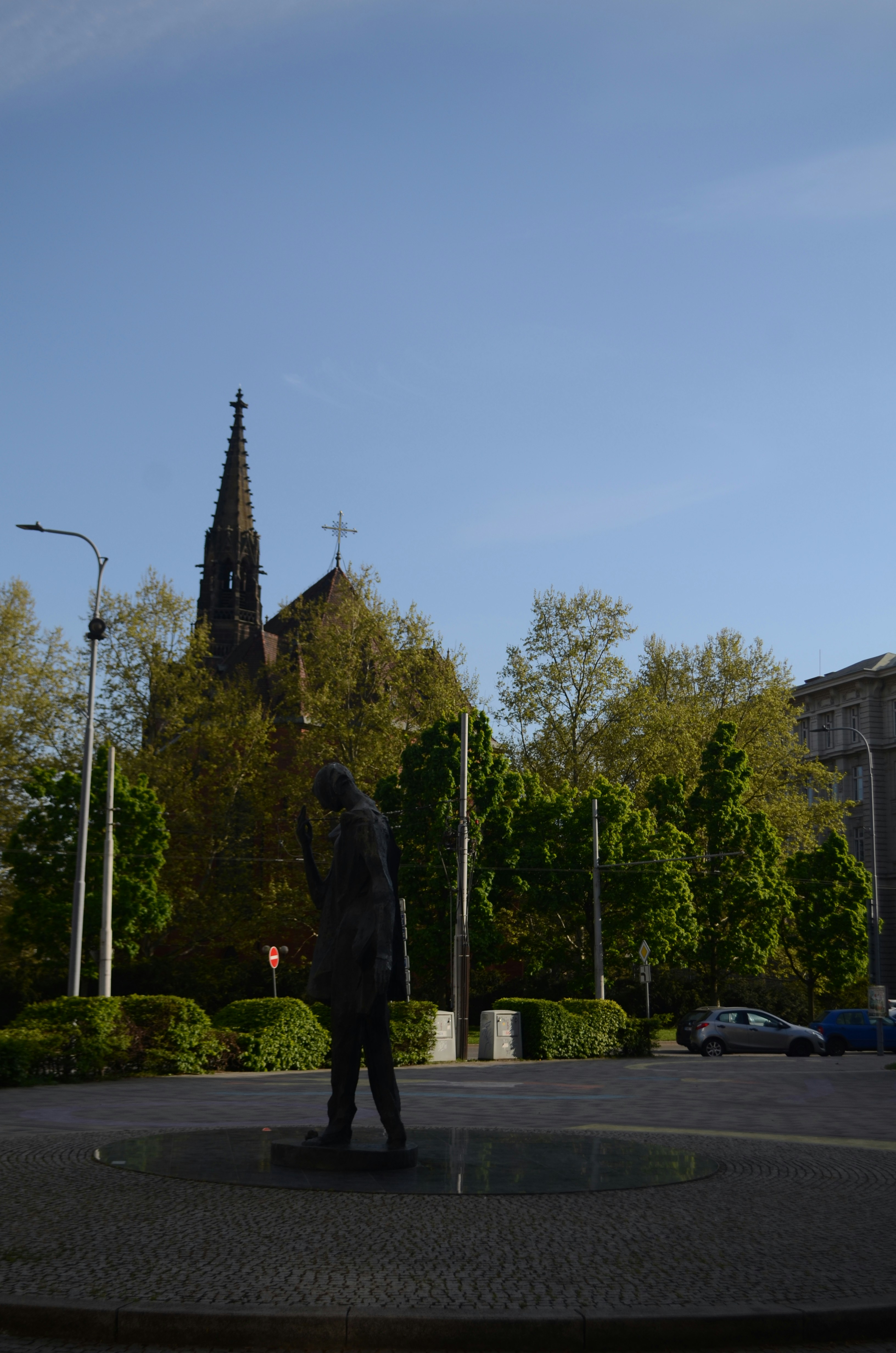 Somber statue, shifting shadows, and a cathedral silhouette