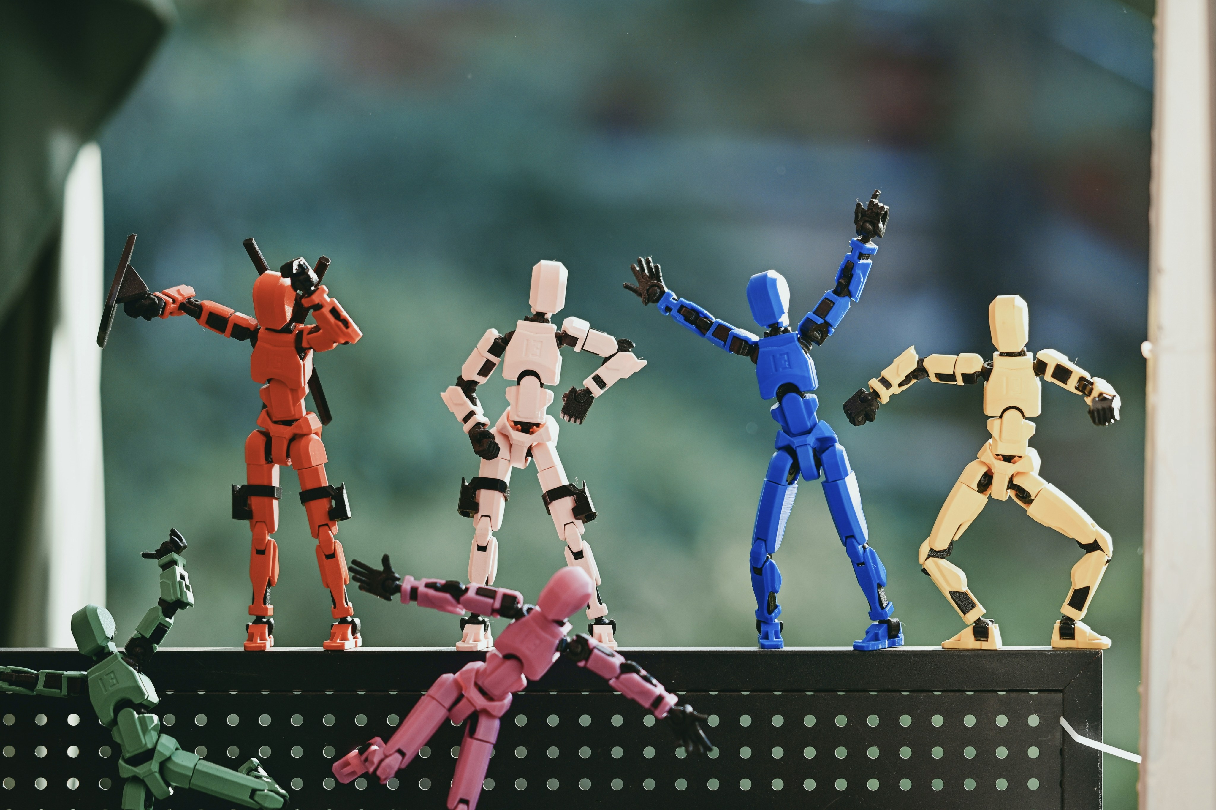 Colorful articulated figures strike a pose on a perforated shelf