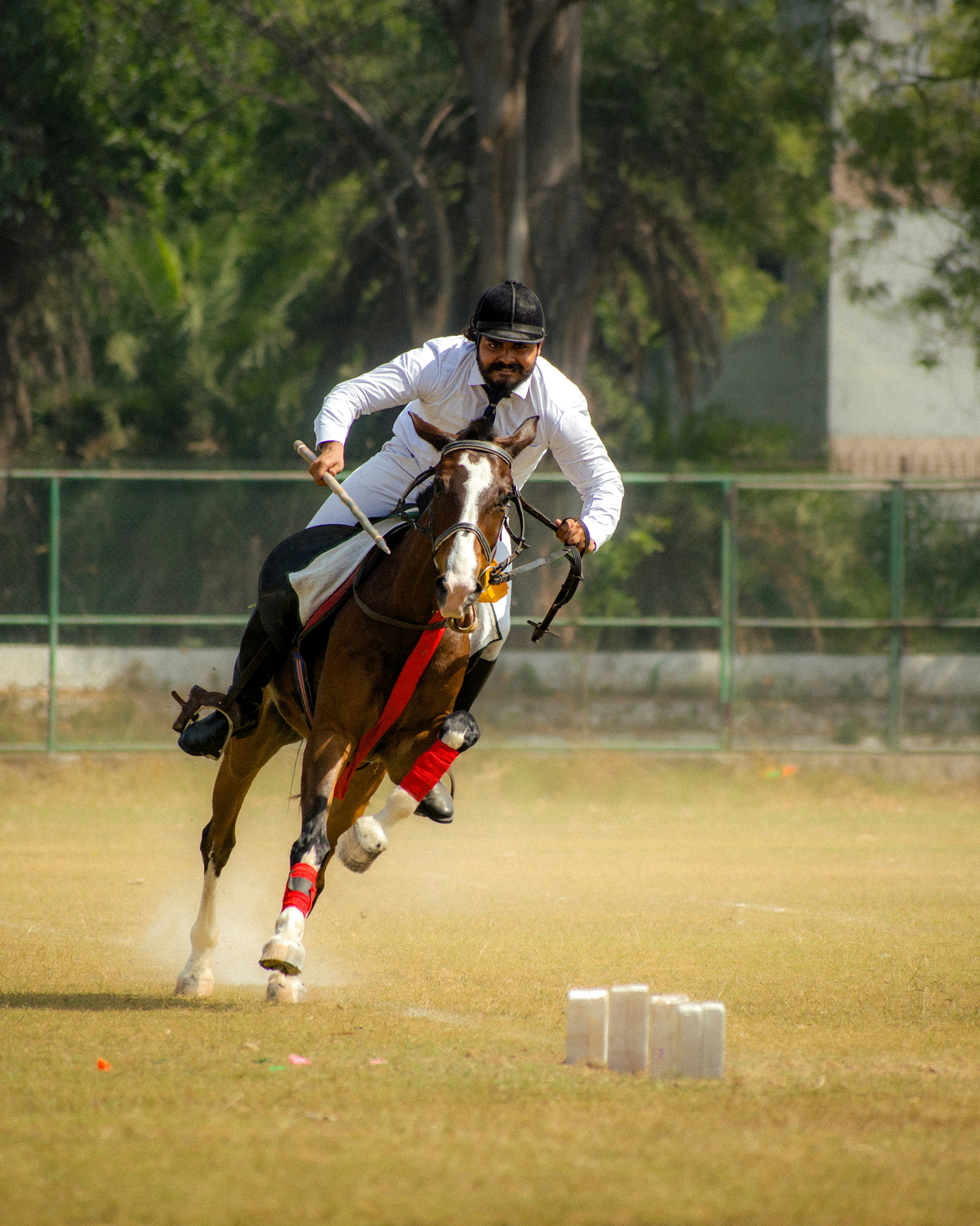 Rider and horse in mid‑turn during barrel‑racing drill on sunlit arena