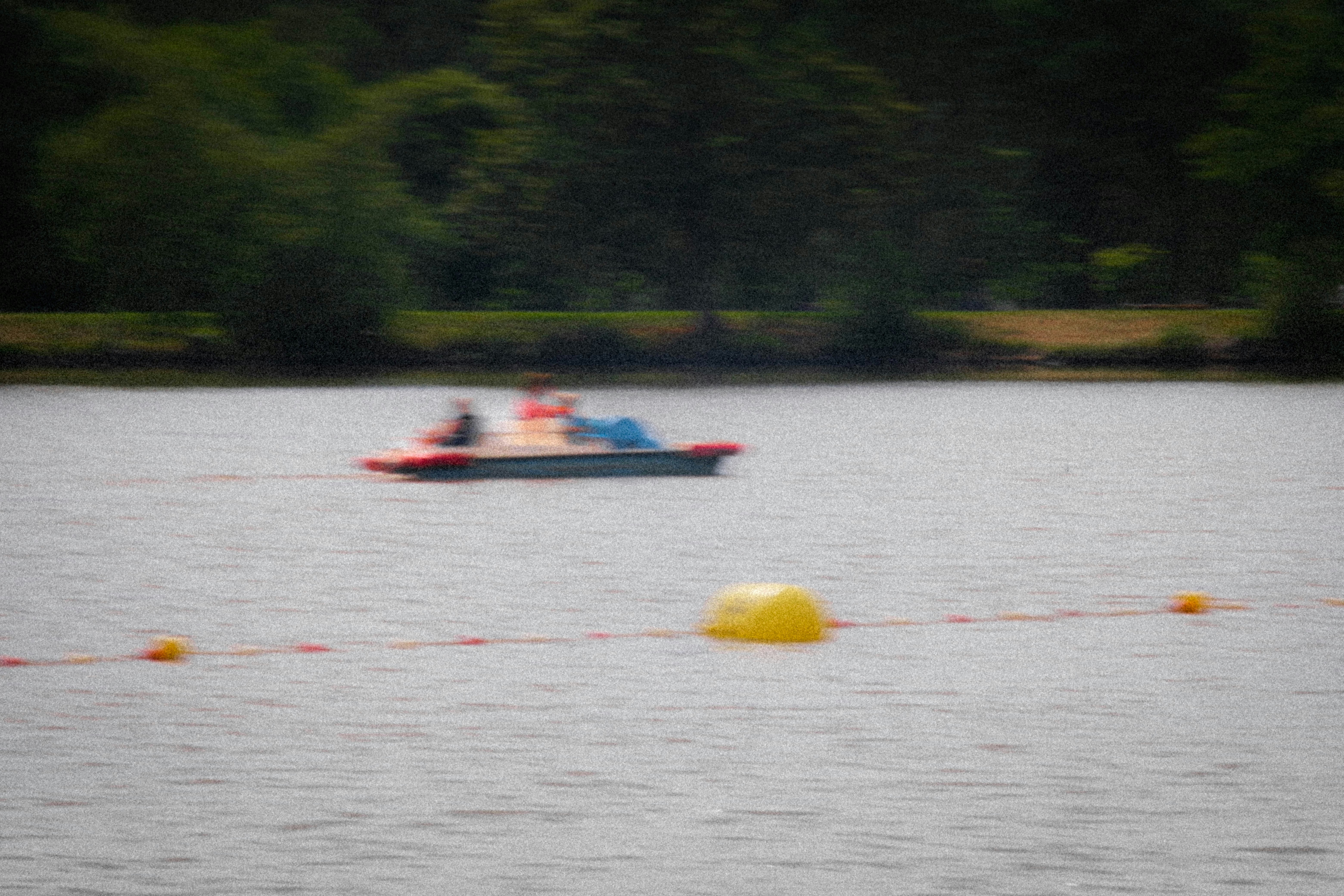 Blurred Boat Drift across Calm Lake with Yellow Buoy