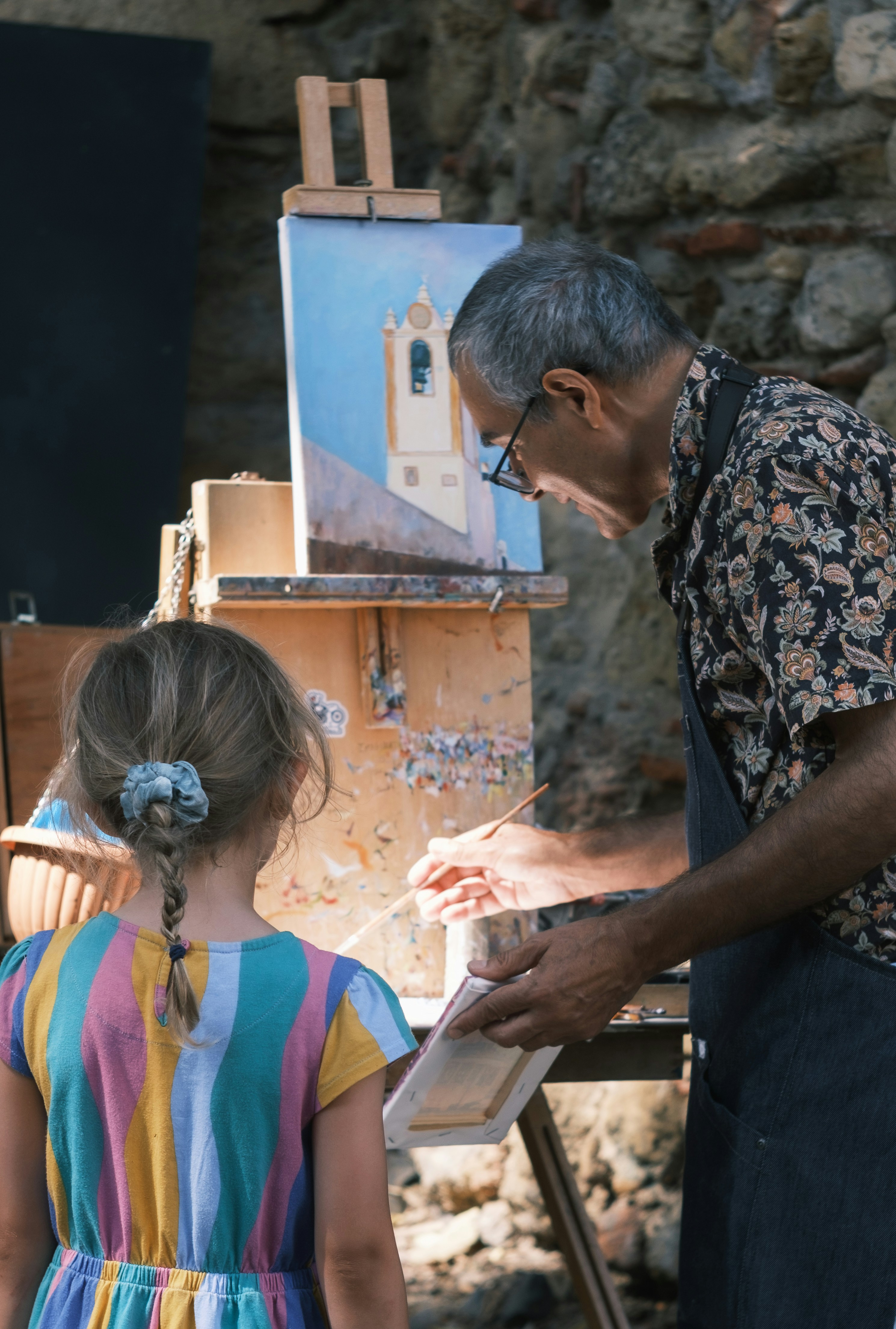 The Painter's Lesson: An Elder Artist Guides a Young Atelier in Soft Sunlight